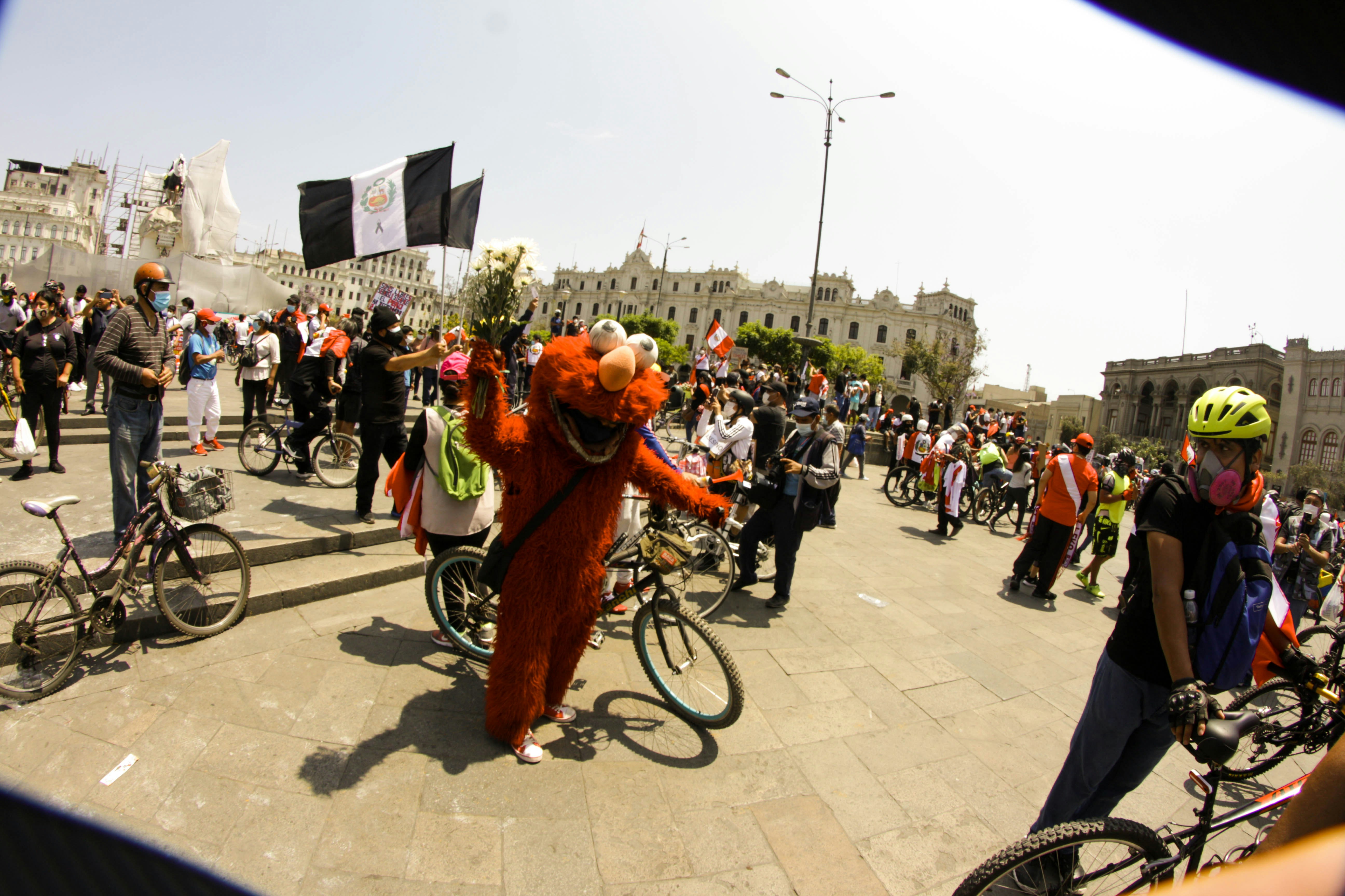 Centre Stage in a City Square: An Orange Mascot Animates a Cyclist Parade