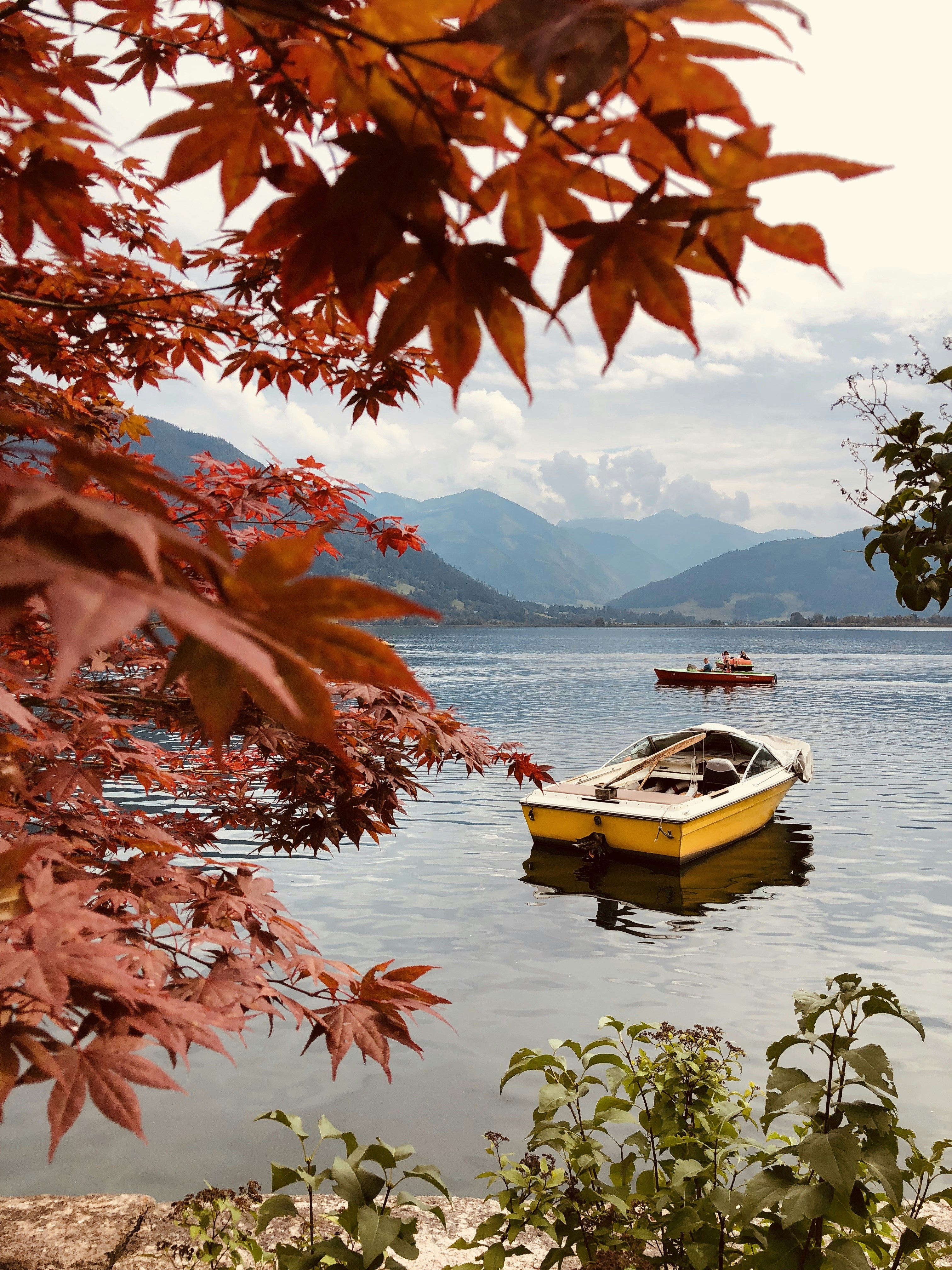 Amber Leaves Framing a Yellow Boat on a Quiet Alpine Lake