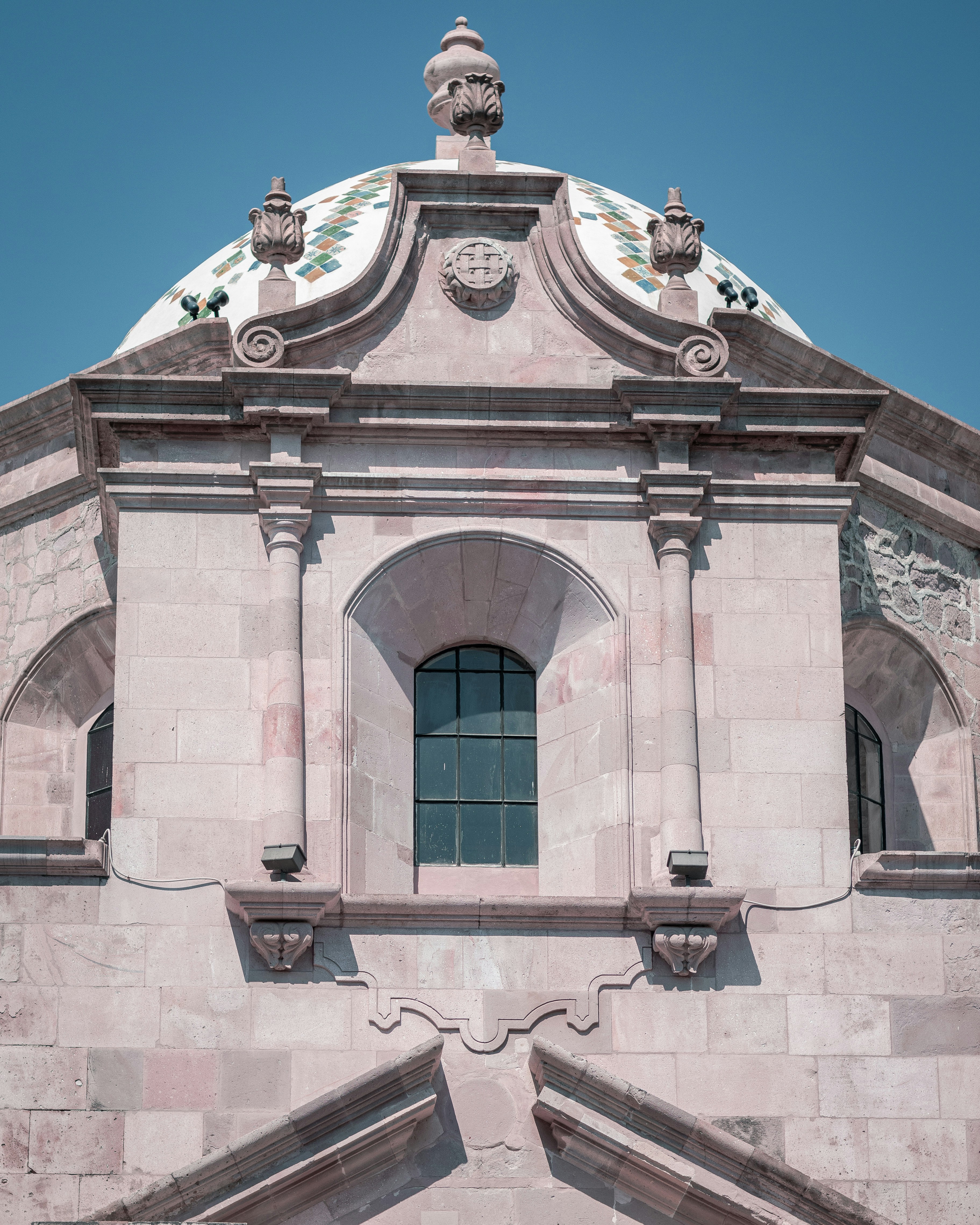 Intricate details of a historic building's facade, showcasing a unique window and decorative elements under a clear blue sky.
