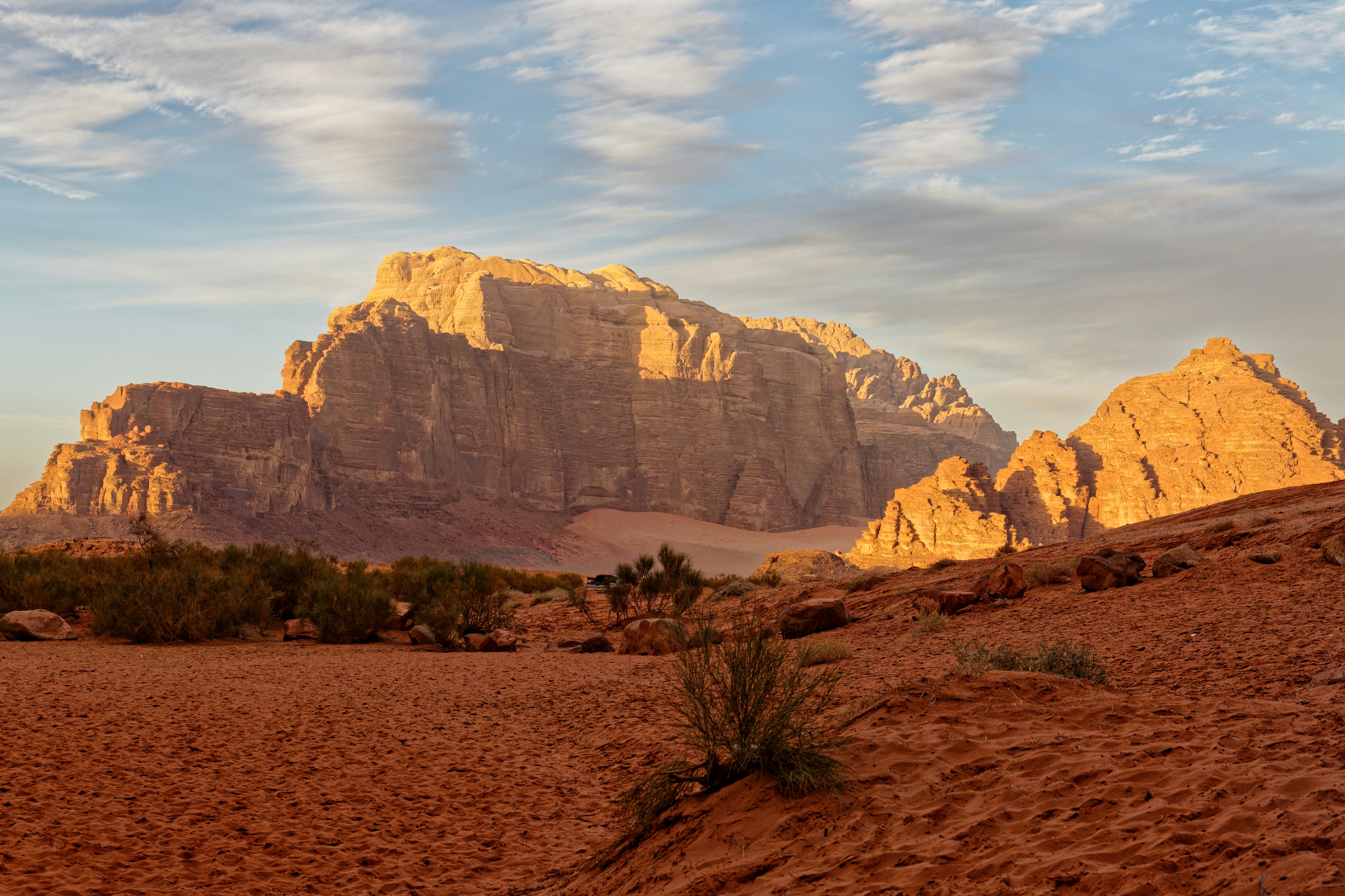 Towering rock formations bathed in warm sunlight under a sky dotted with soft clouds.