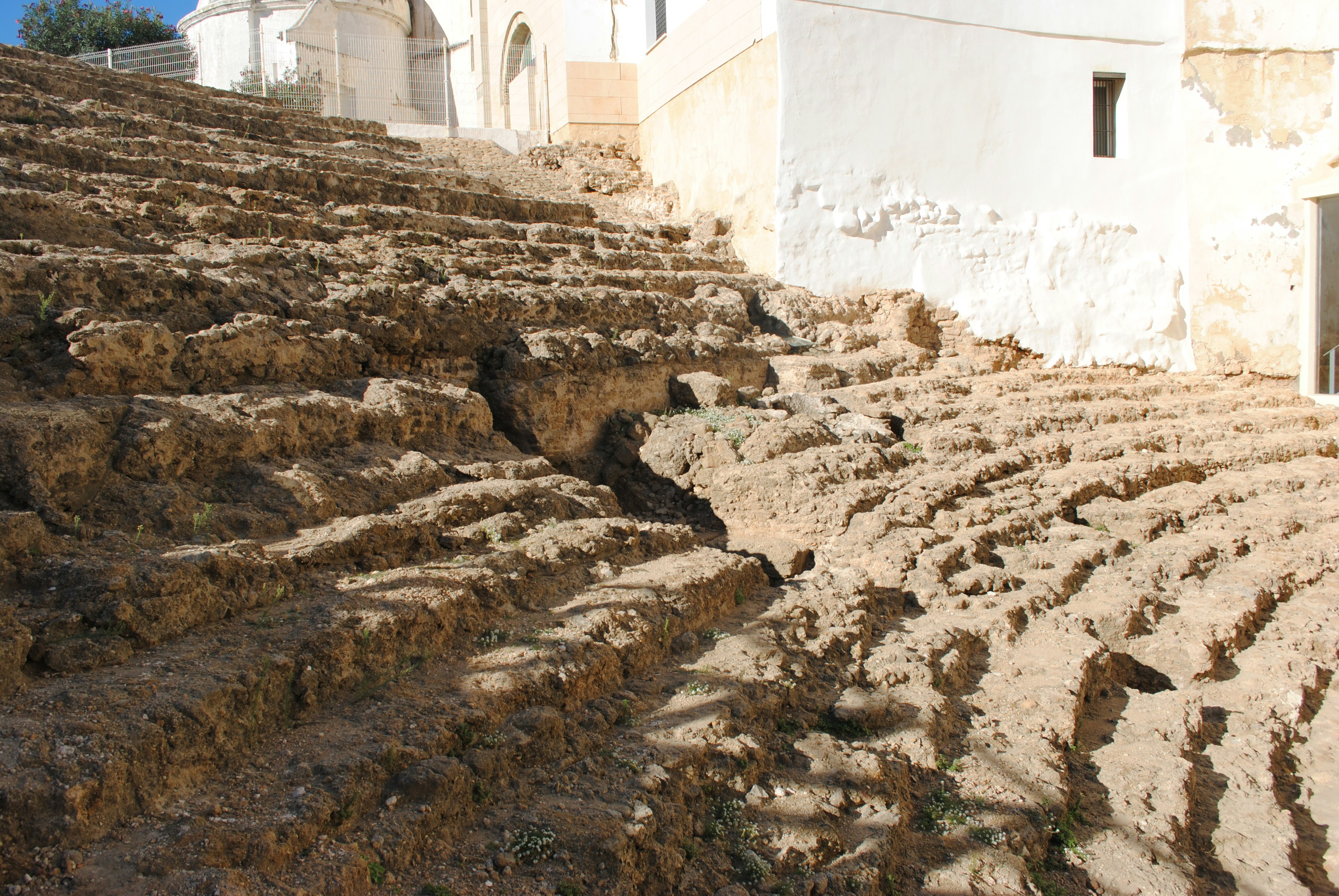 Sunlit stone tiers of an ancient Roman theatre with weathered textures in Cadiz.