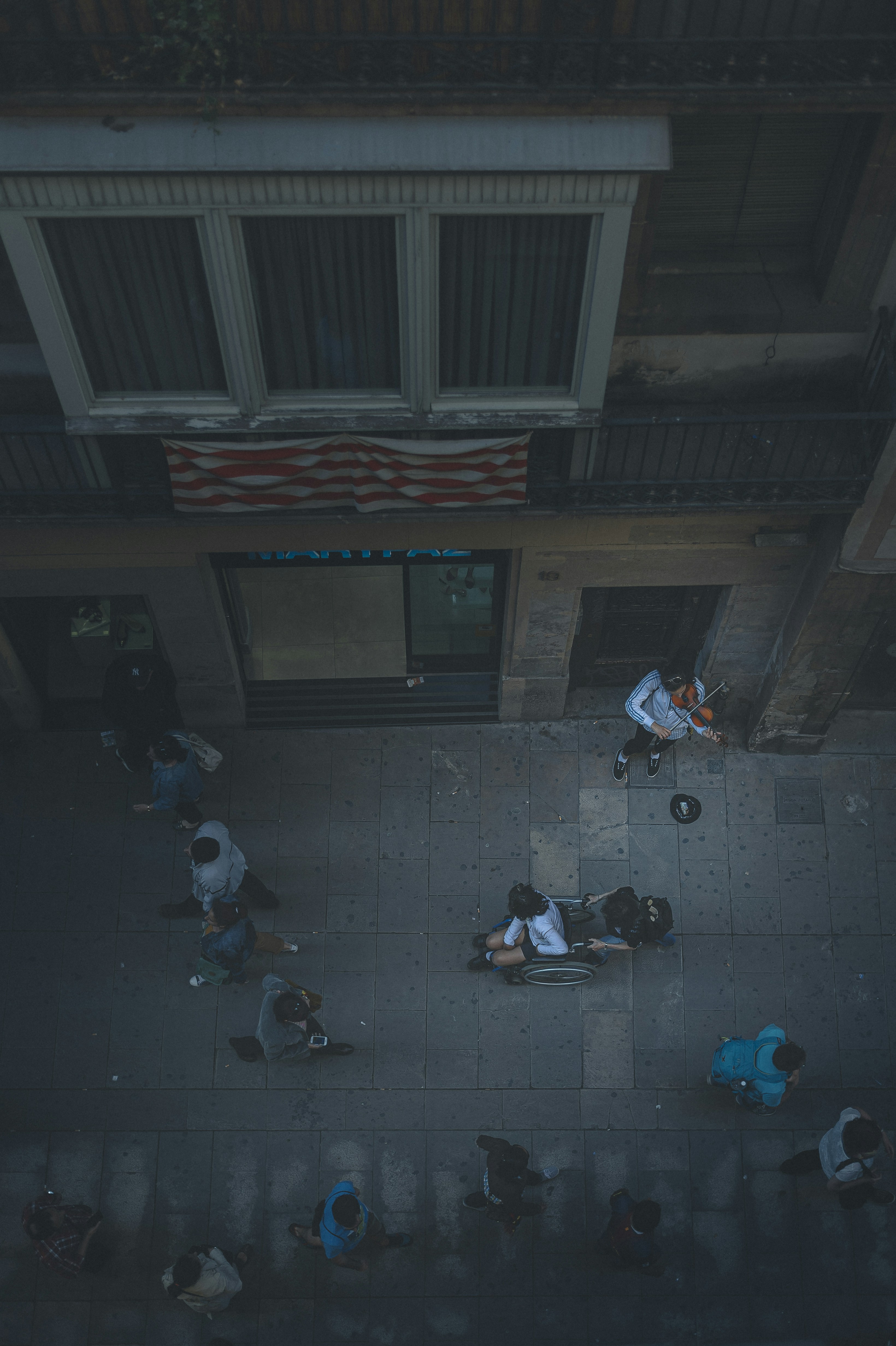 A Quiet Street from Above: People and Piano in a Shadowed Block
