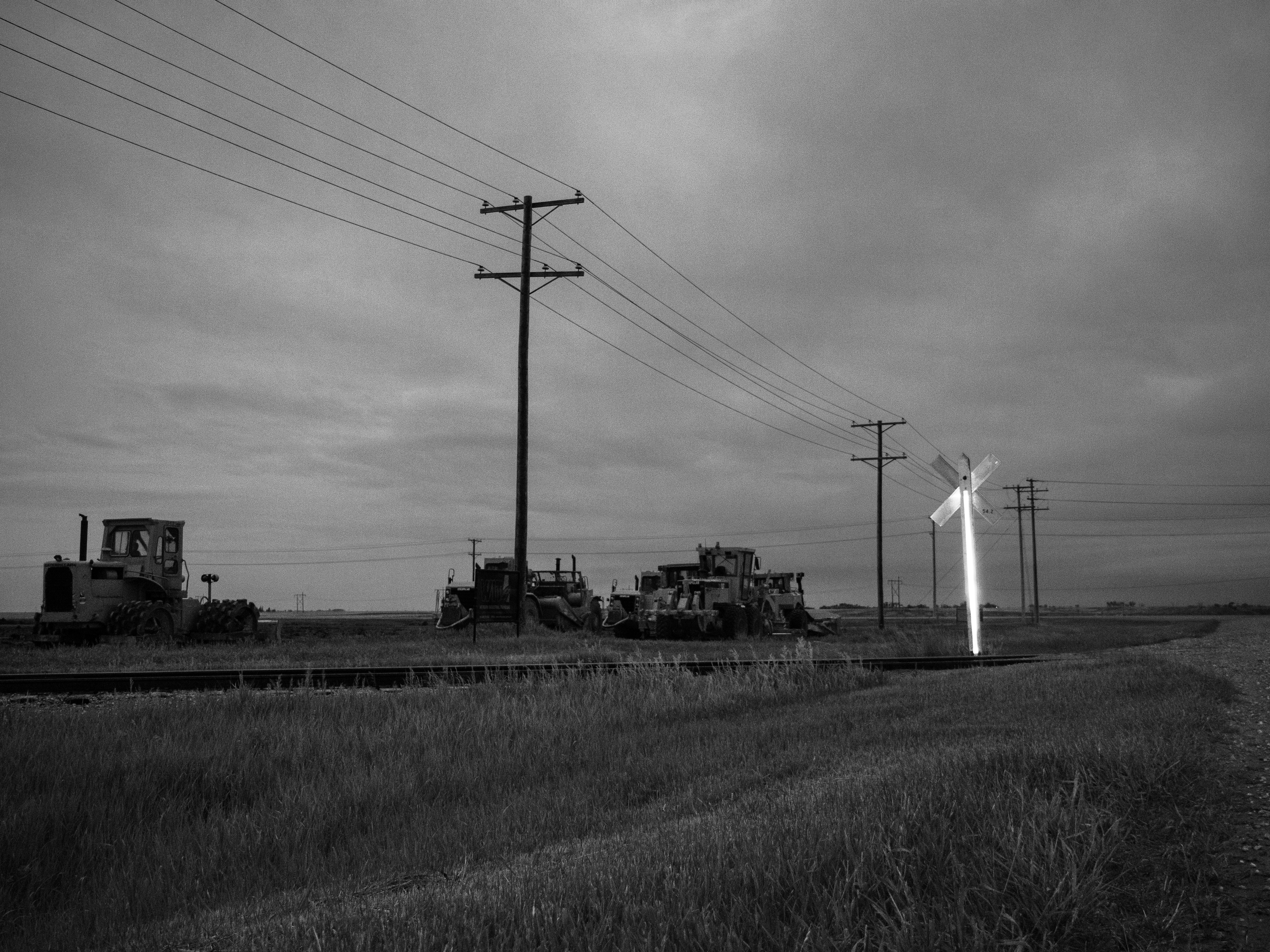 Railroad Quiet: Tractors and Crossing in a Monochrome Field