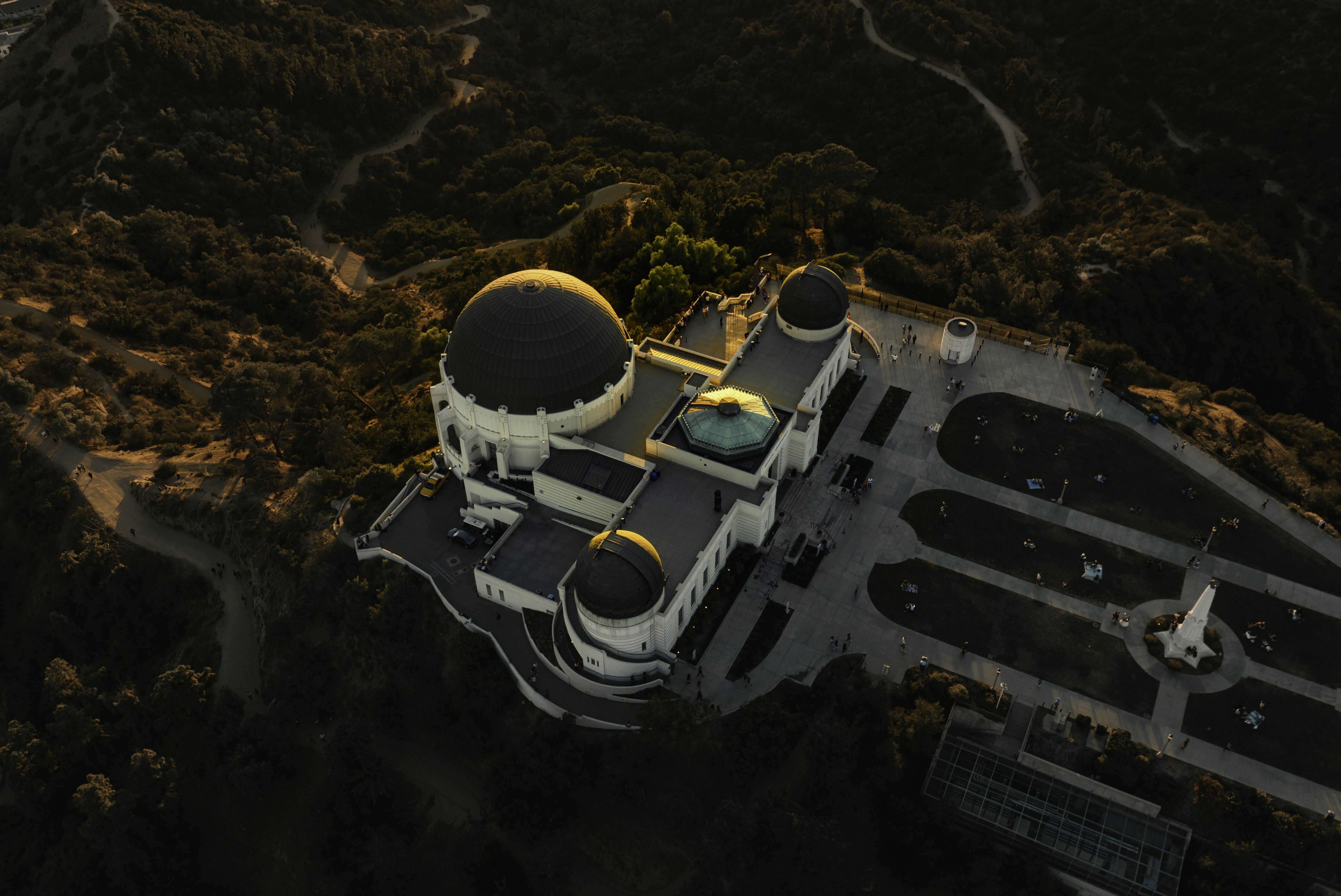 Griffith Observatory bathed in warm sunset light with surrounding green landscape.