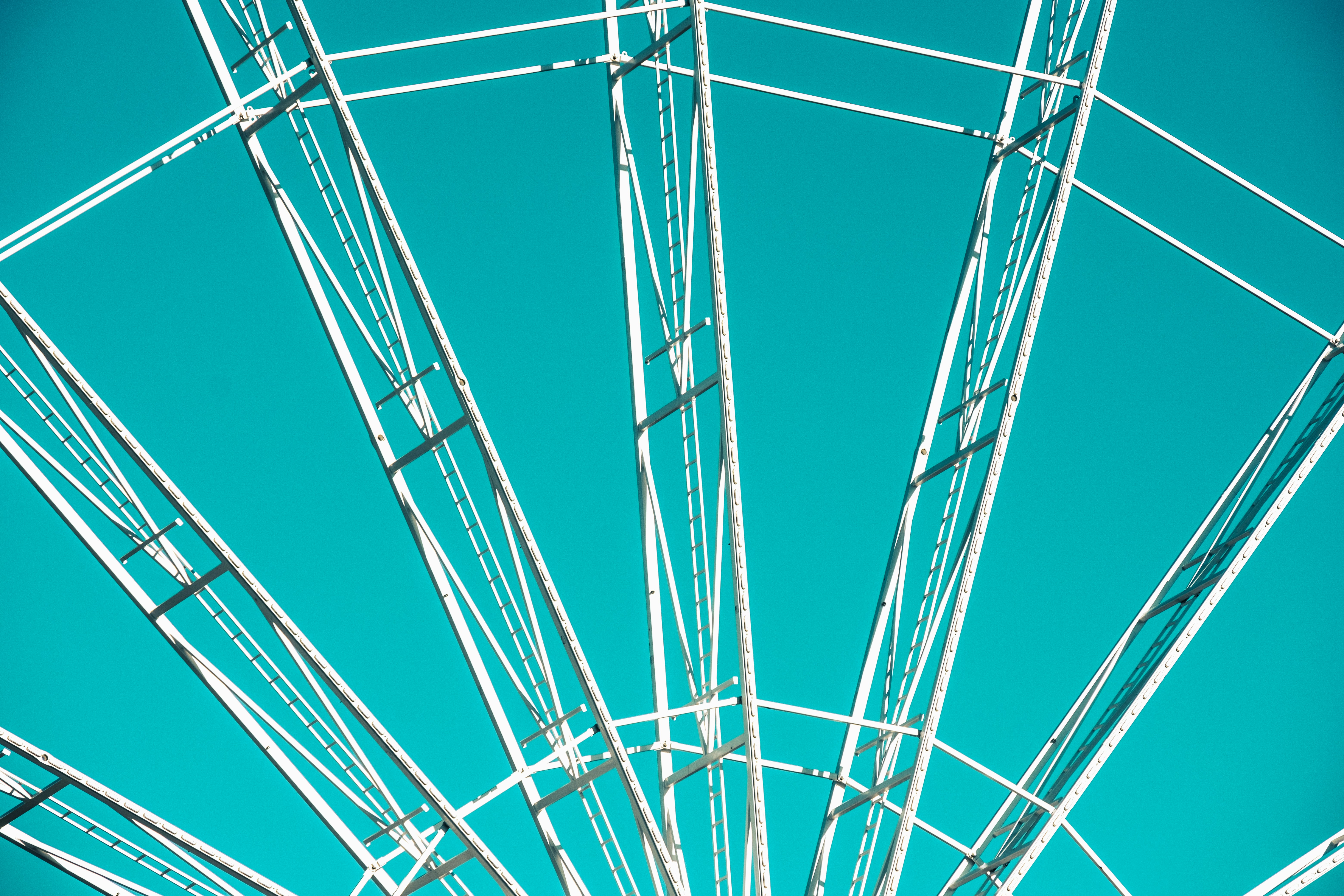 Teal Sky, White Lattice: Converging Ferris Wheel Spokes