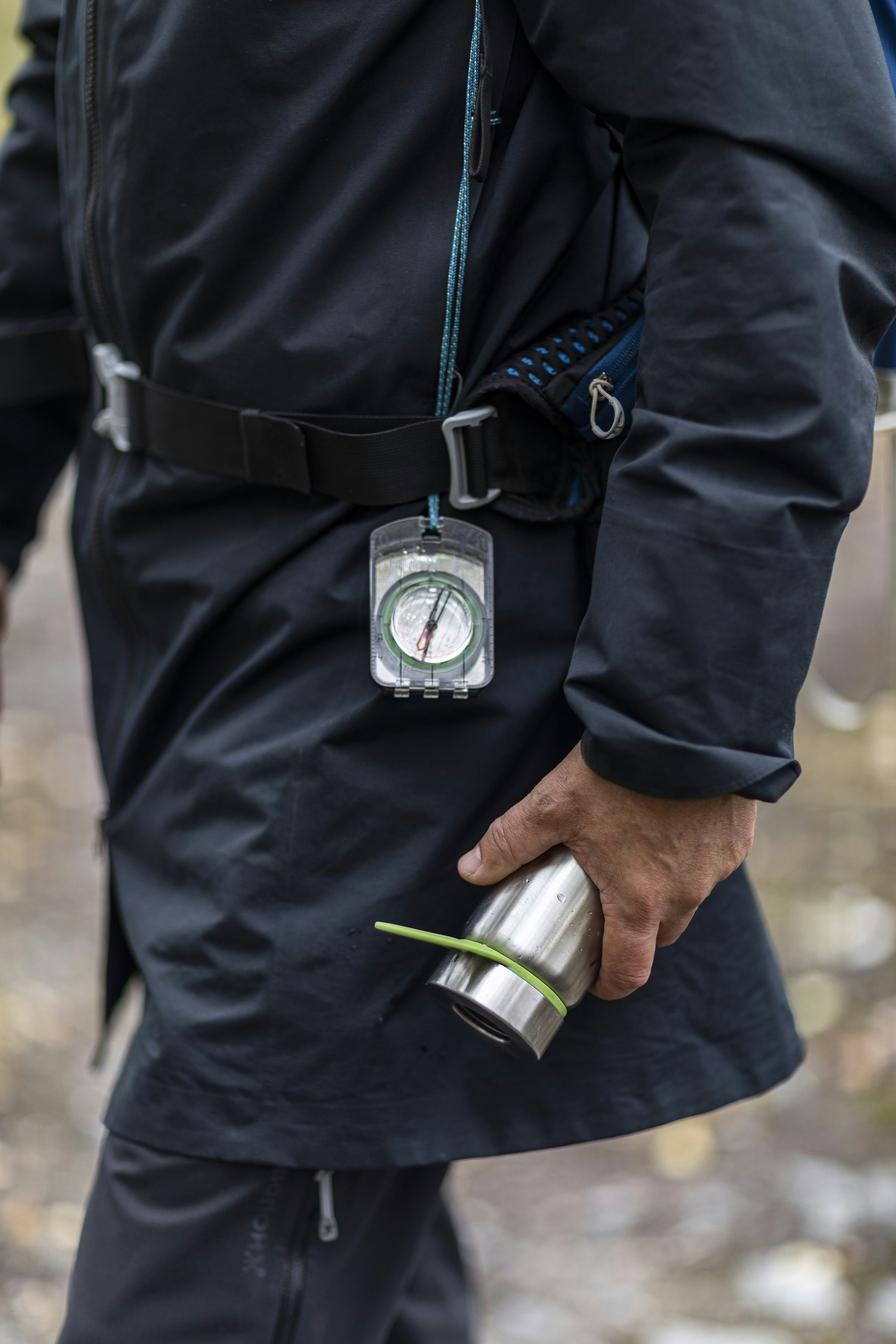 Trail-Ready Portrait: Compass, Lanyard, and Stainless Cup on a Hiker's Jacket