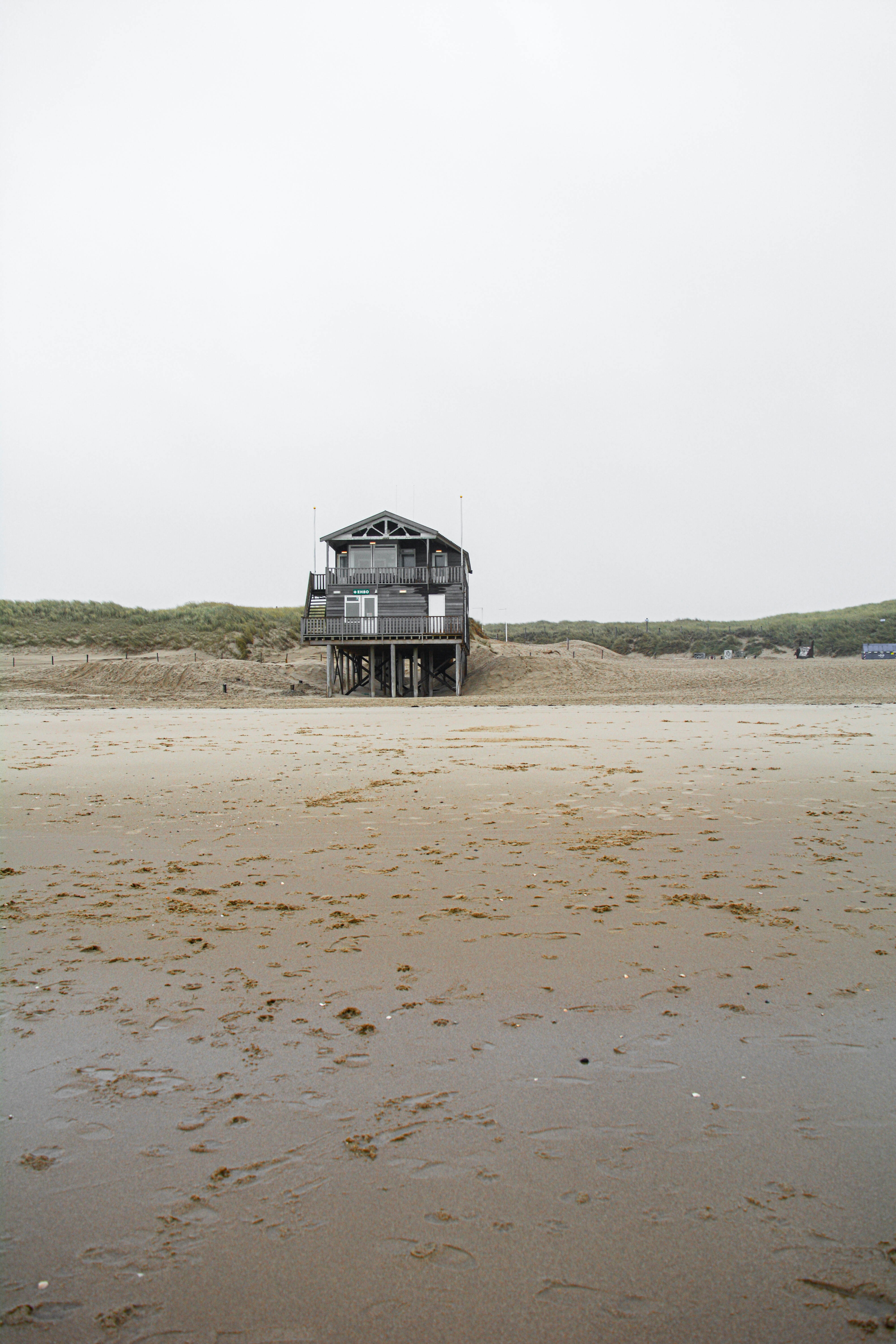 Lifeguard House on Stilts Amid a Quiet Dune Beach under a Pale Sky