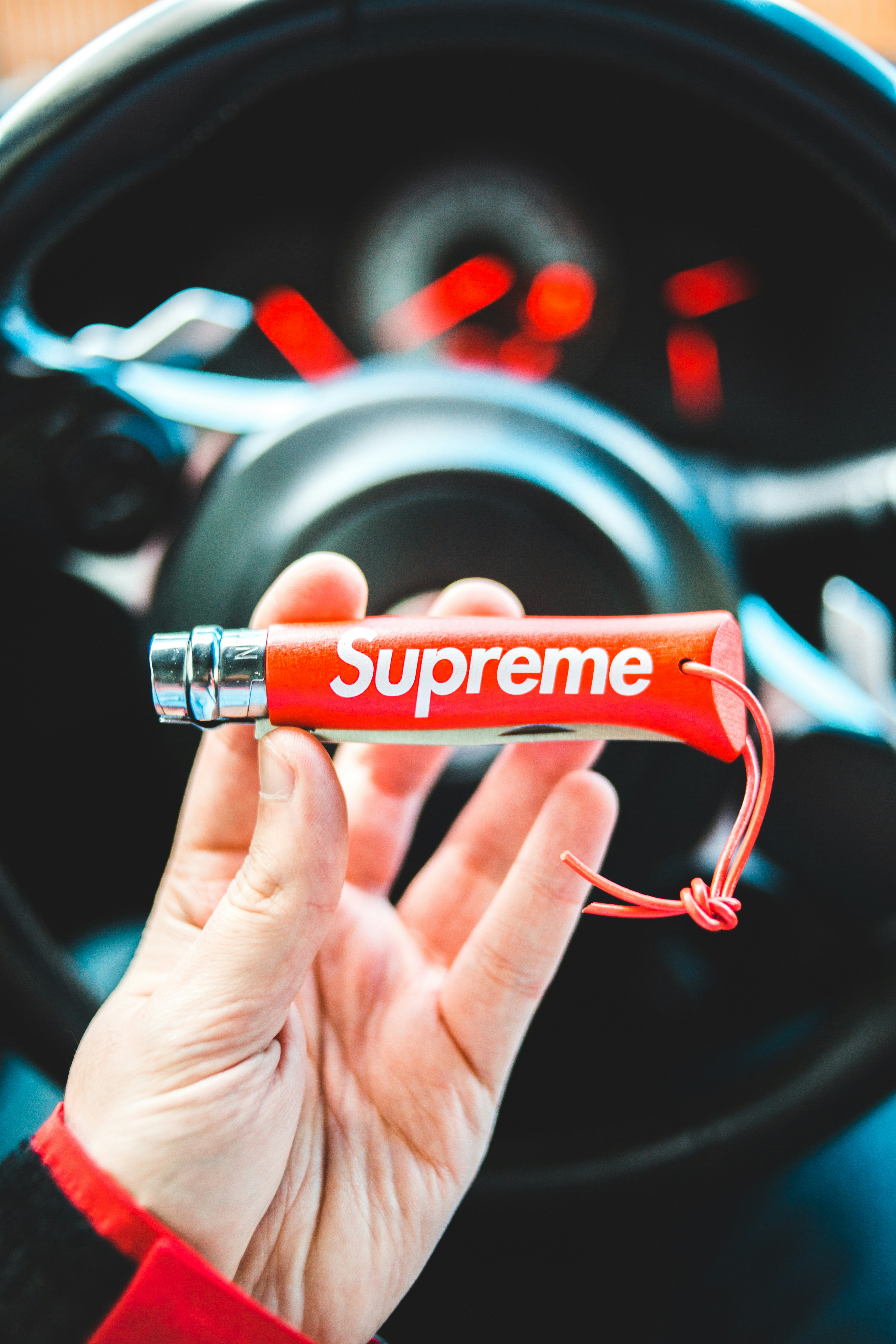 Supreme on the Move: a red keychain held before a blurred car cockpit