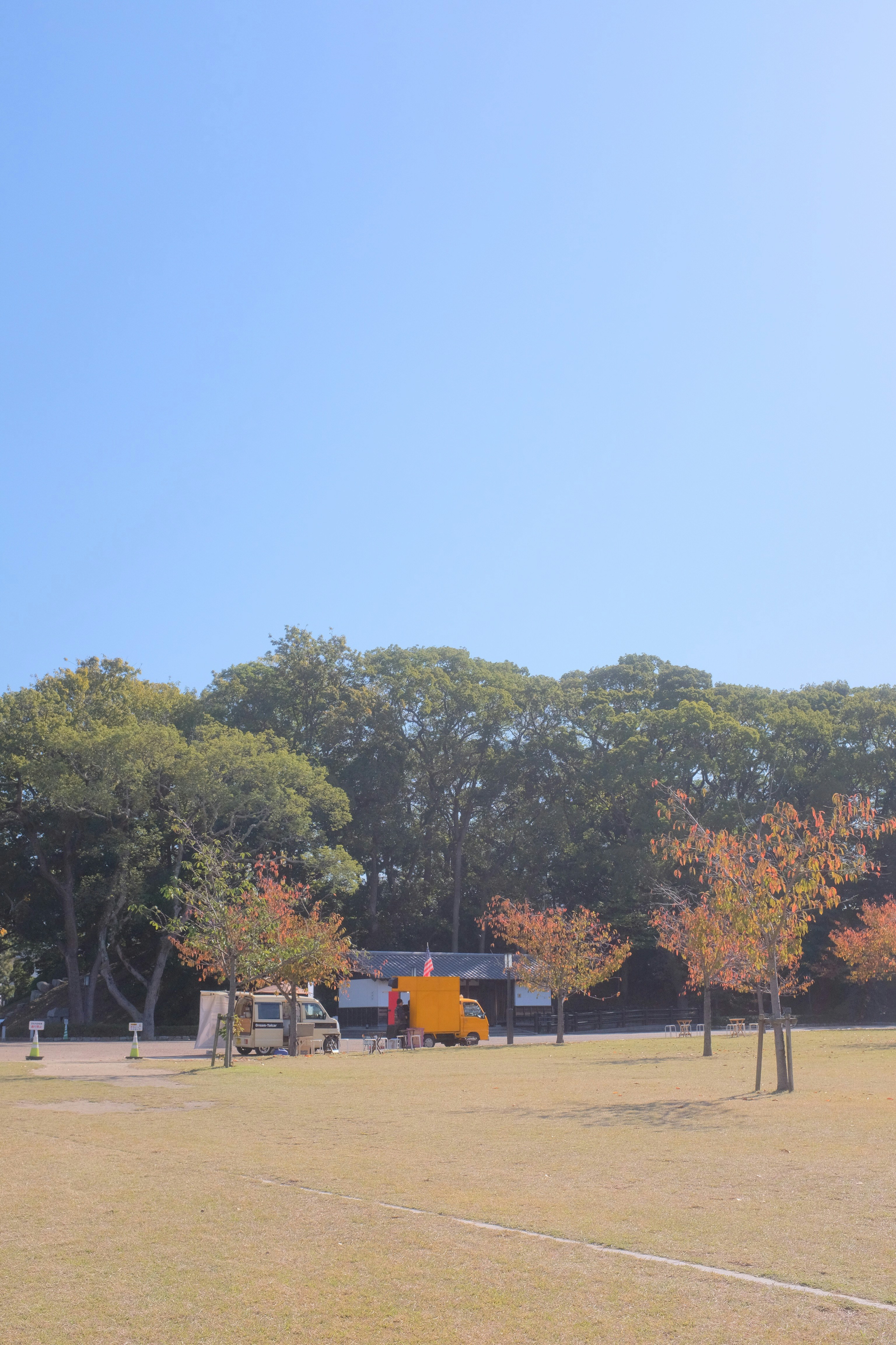 Yellow Truck at the Park's Edge under a Clear Blue Sky