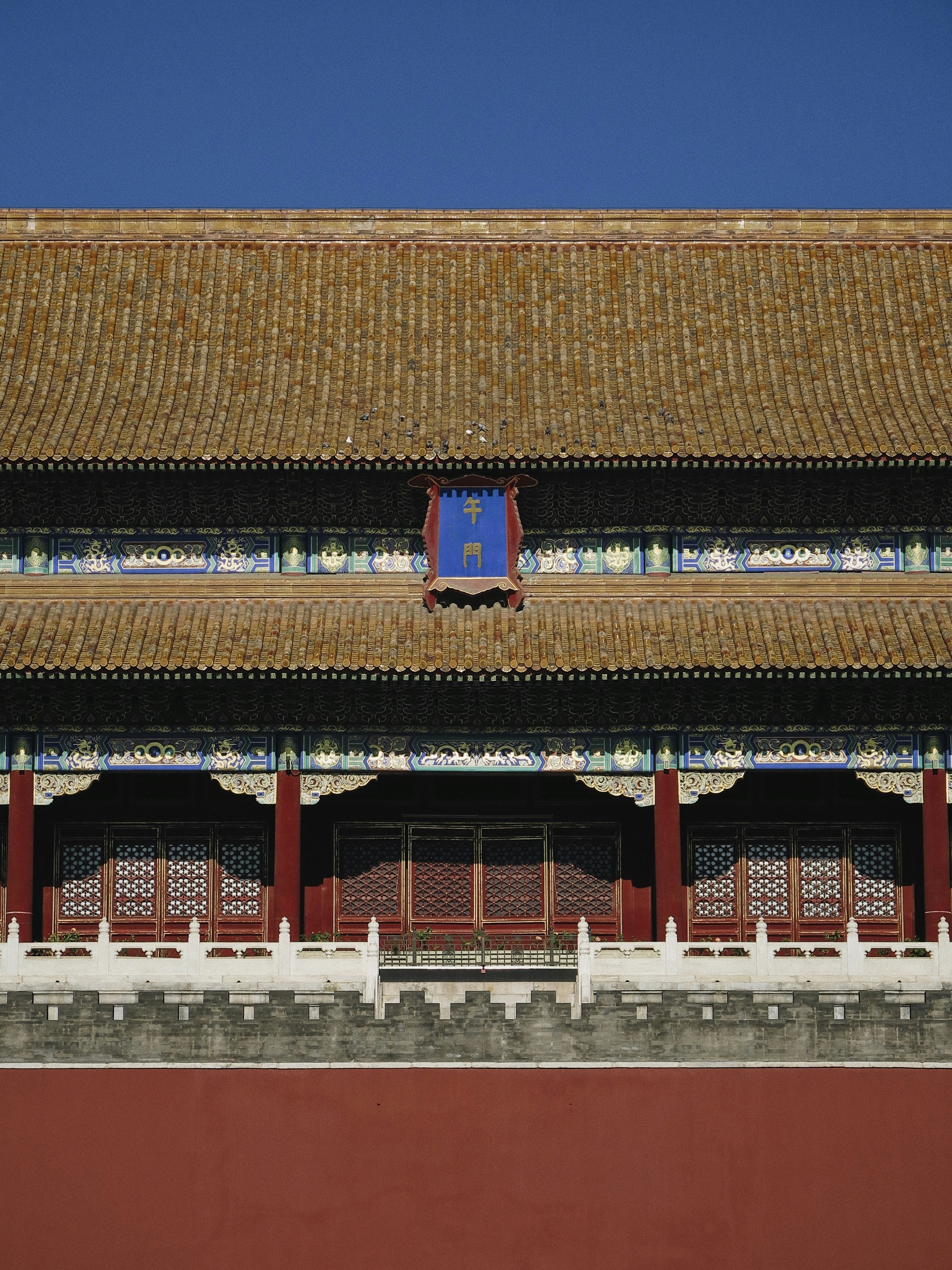Traditional Chinese architecture featuring intricate roof details and vibrant colors against a clear blue sky.