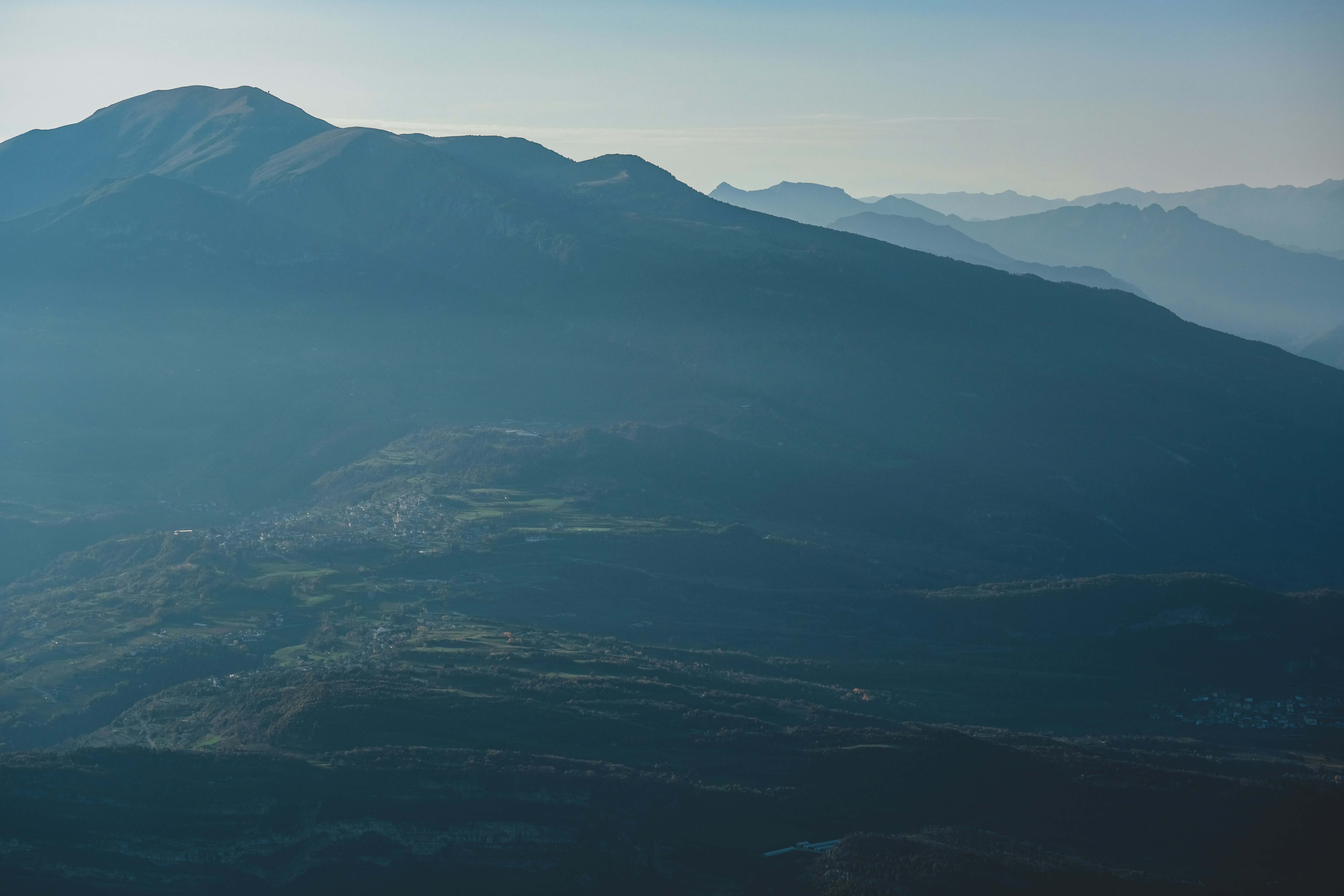 Dramatic mountain landscape shrouded in mist, revealing layers of peaks and valleys under soft morning light.