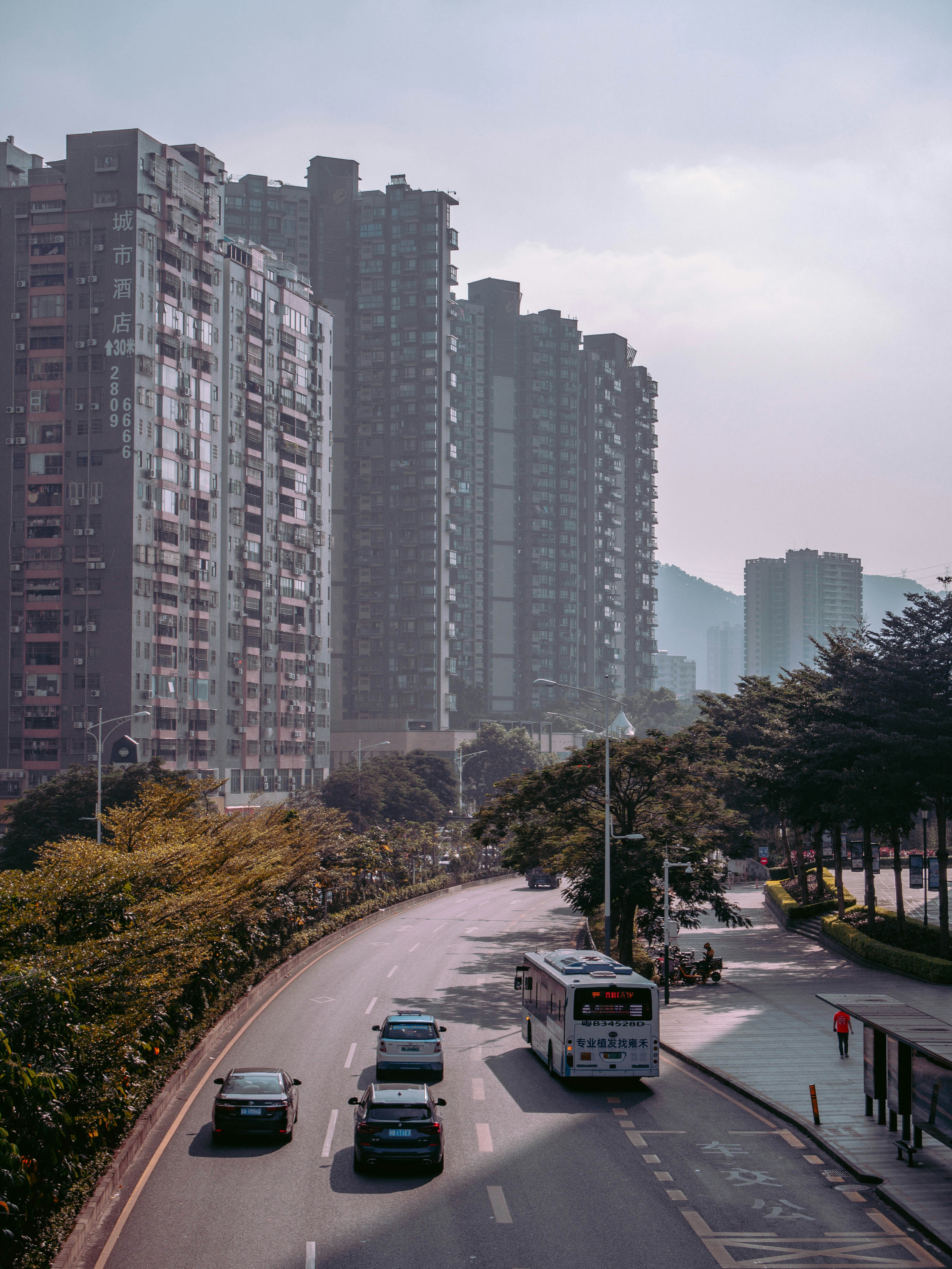 A bustling city scene showcasing a winding road flanked by towering residential buildings and lush greenery. The image captures the dynamic interplay between urban architecture and nature.