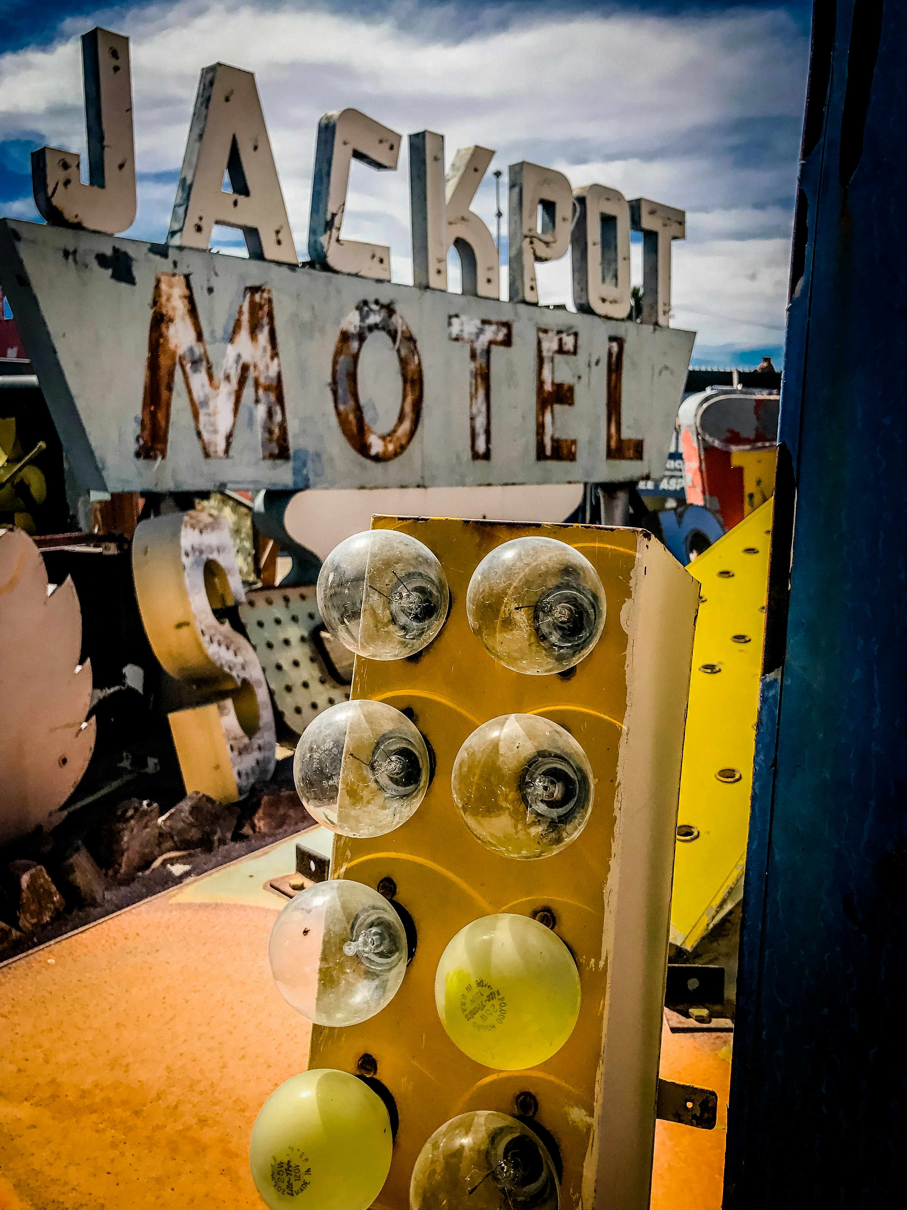 Weathered Jackpot Motel sign with vintage bulbs and colorful letters against a bright sky.