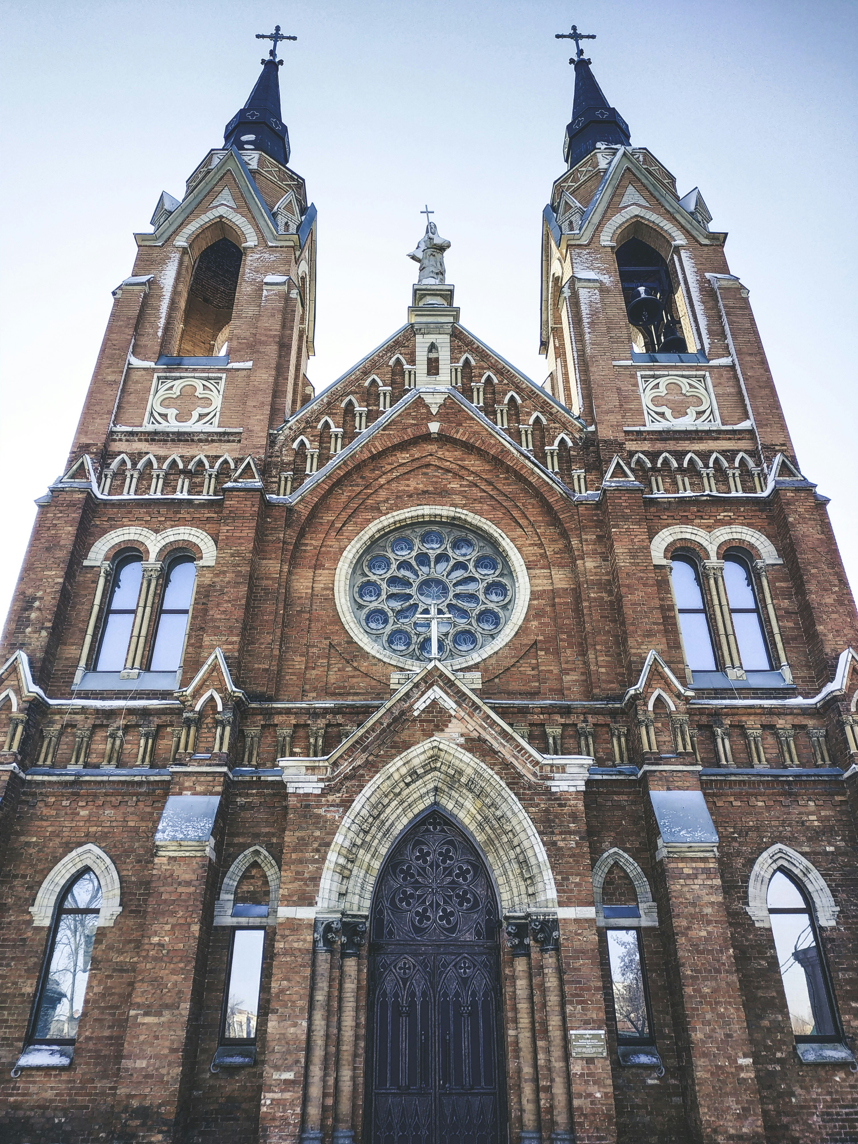 Majestic brick church with twin spires and intricate stained glass, showcasing Gothic architectural elements.
