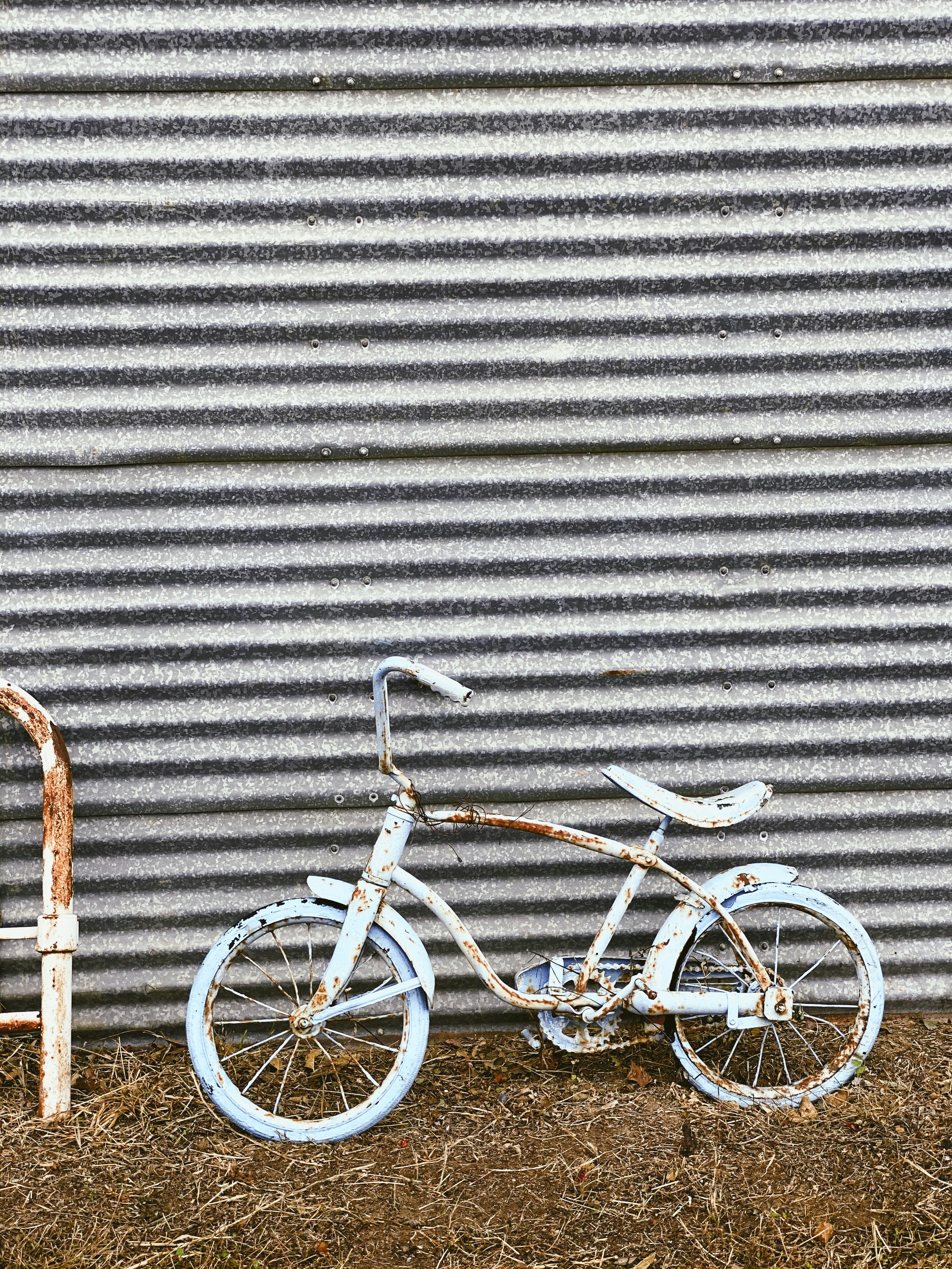 Weathered blue bicycle leaning against a textured gray wall, symbolizing nostalgia and the passage of time.