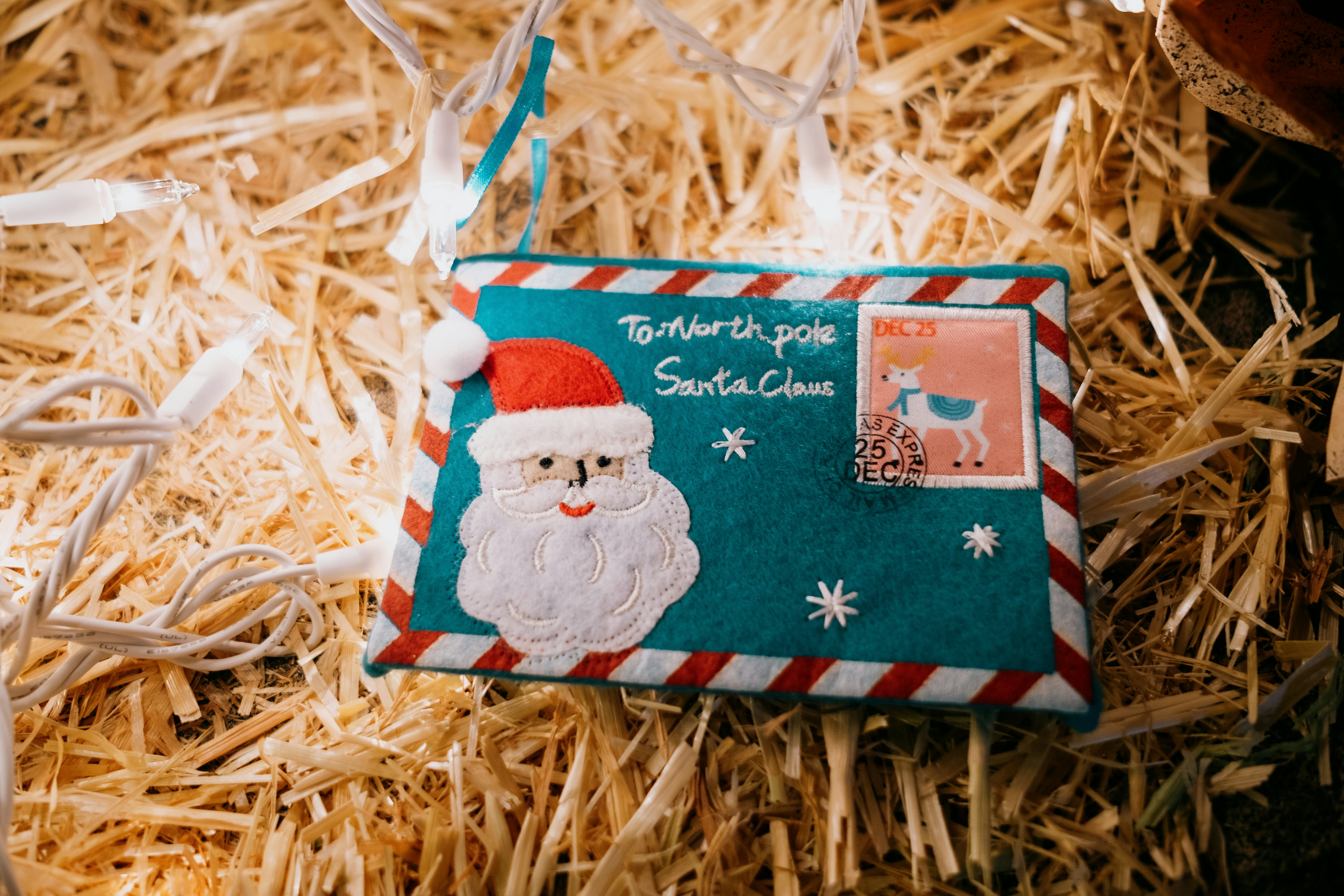 Teal Santa Card Resting on Straw, Bathed in Nostalgic Holiday Warmth