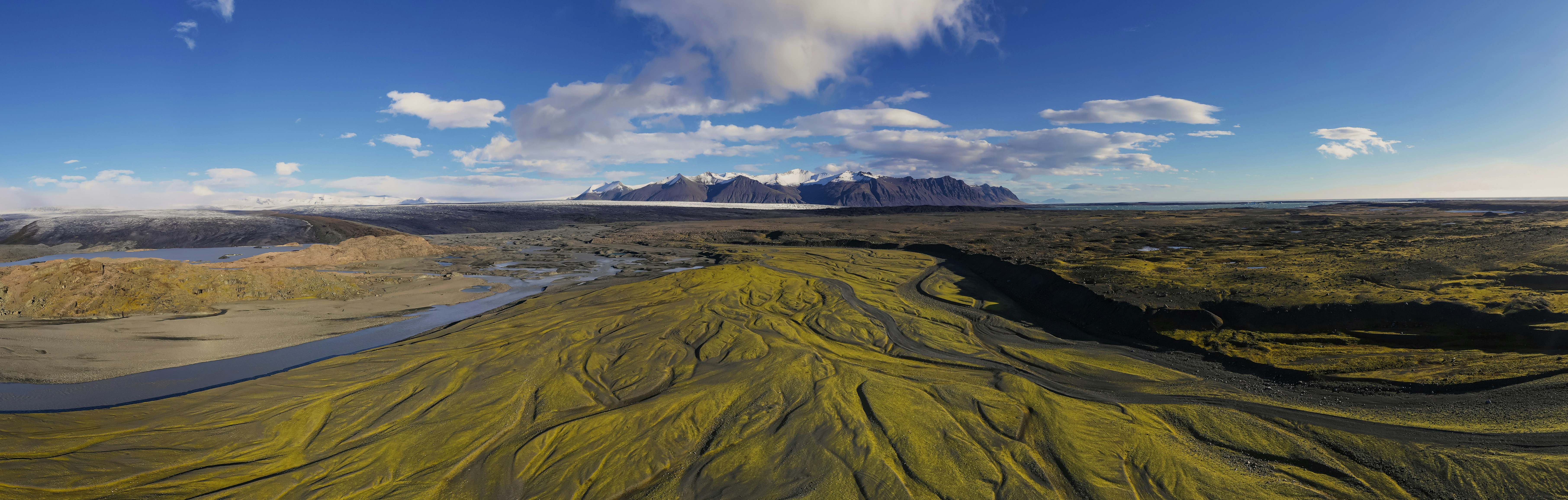 Golden Moss Delta: Aerial Pathway to a Distant Mountain Horizon