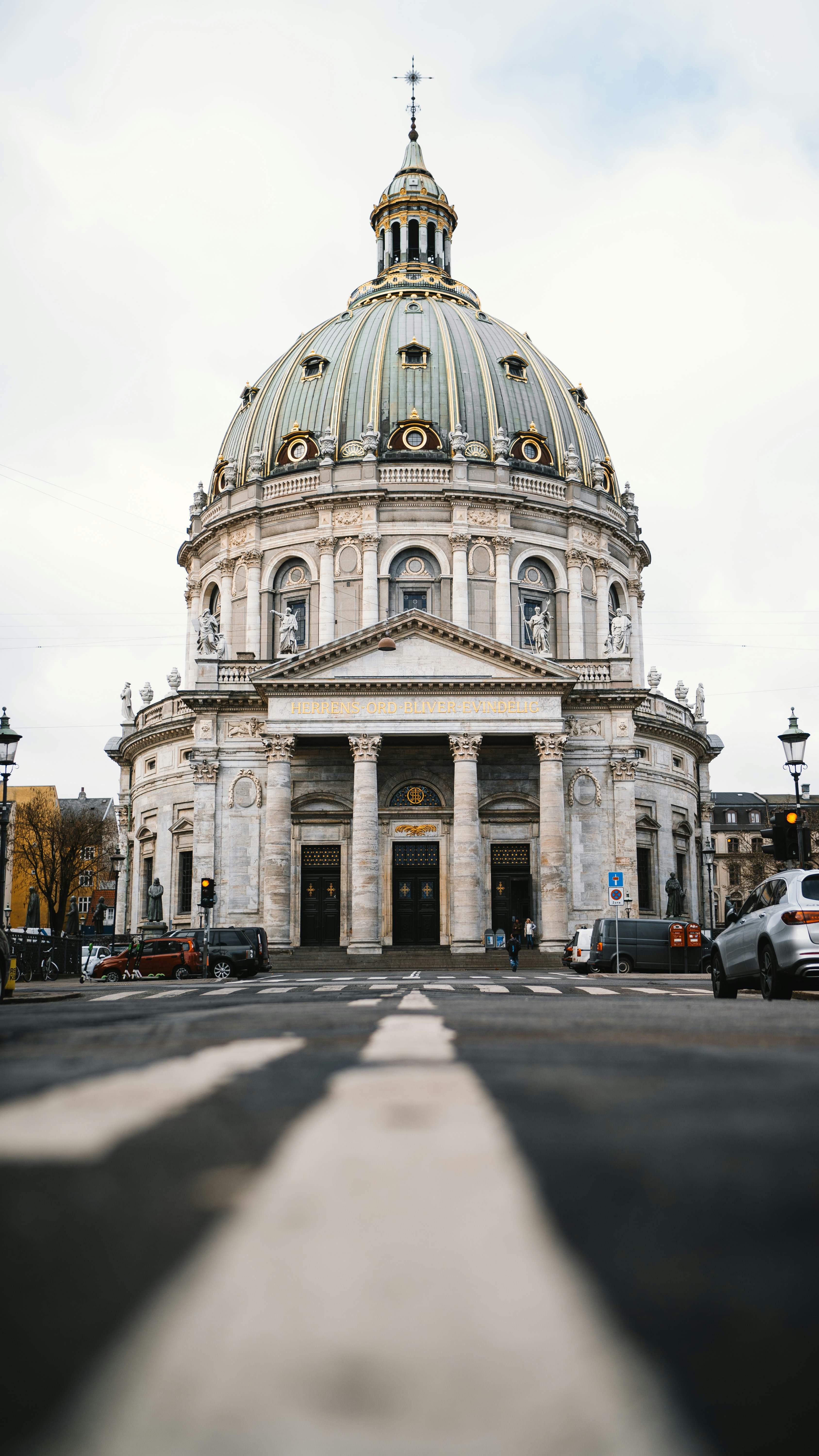 A grand dome of a historic building, showcasing intricate architectural details and a vibrant street scene below.