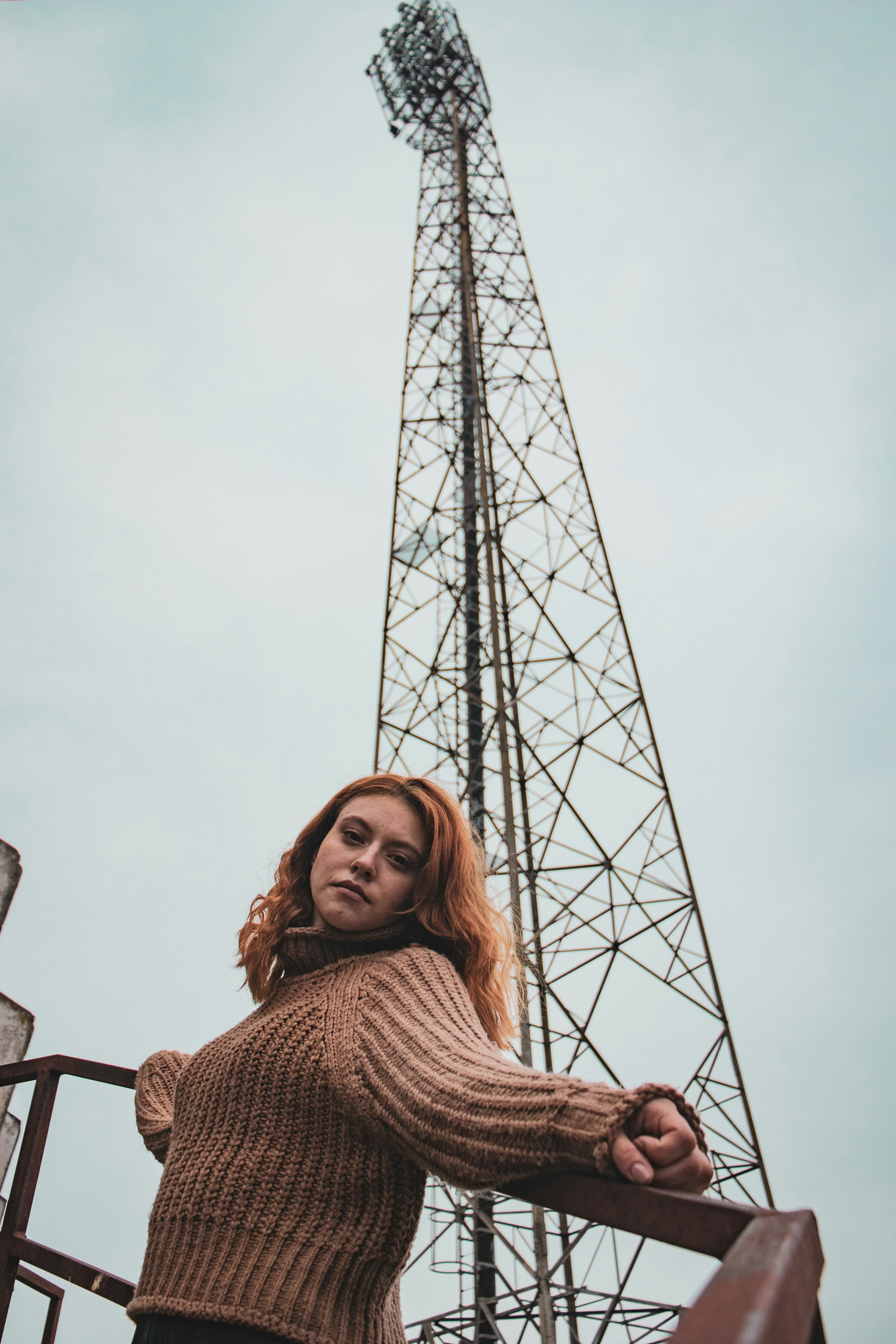 woman in brown and white striped long sleeve shirt standing near tower during daytime