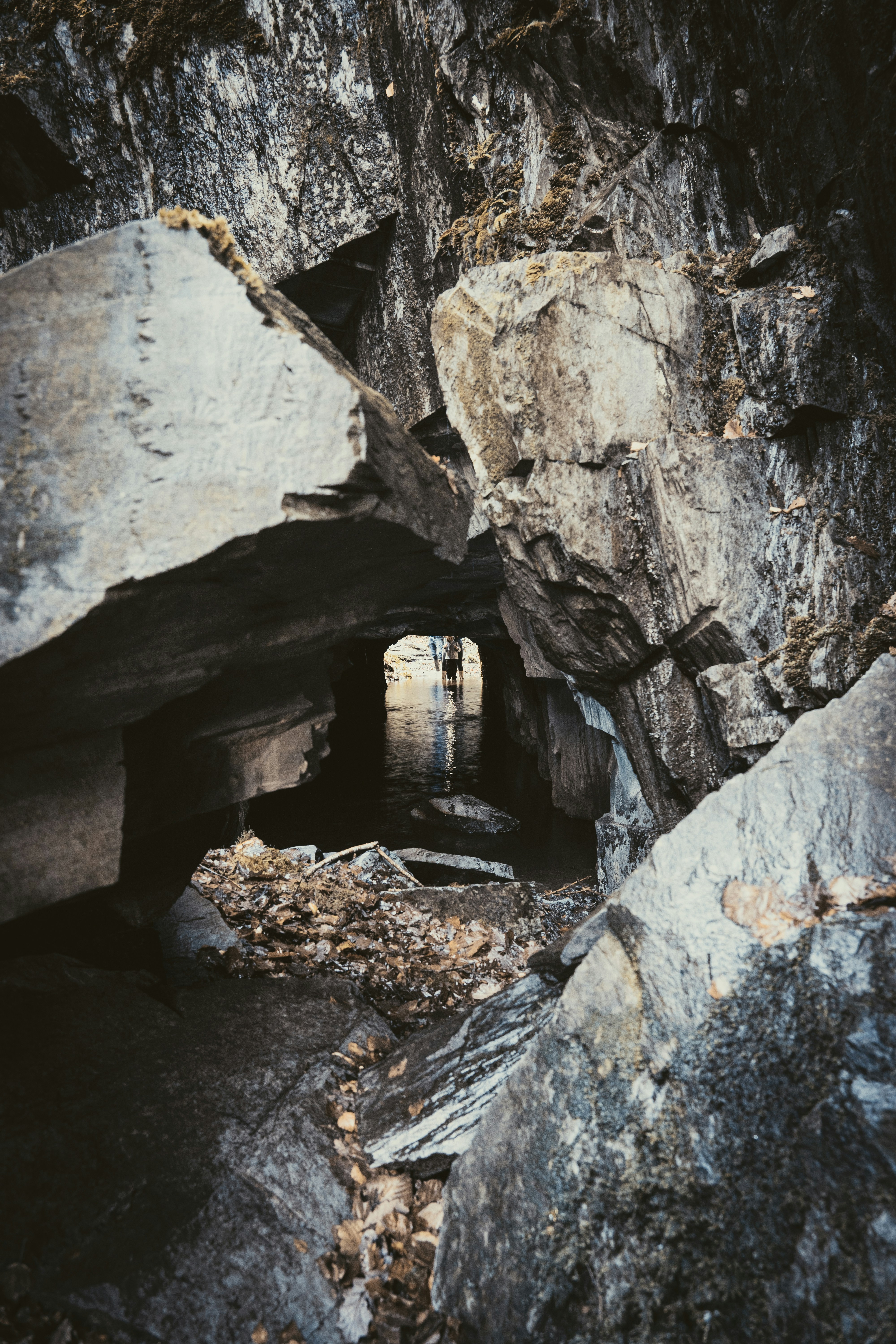 A rocky cavern framed by jagged stones, revealing a serene waterway beyond. The interplay of light and shadow creates an enchanting atmosphere.