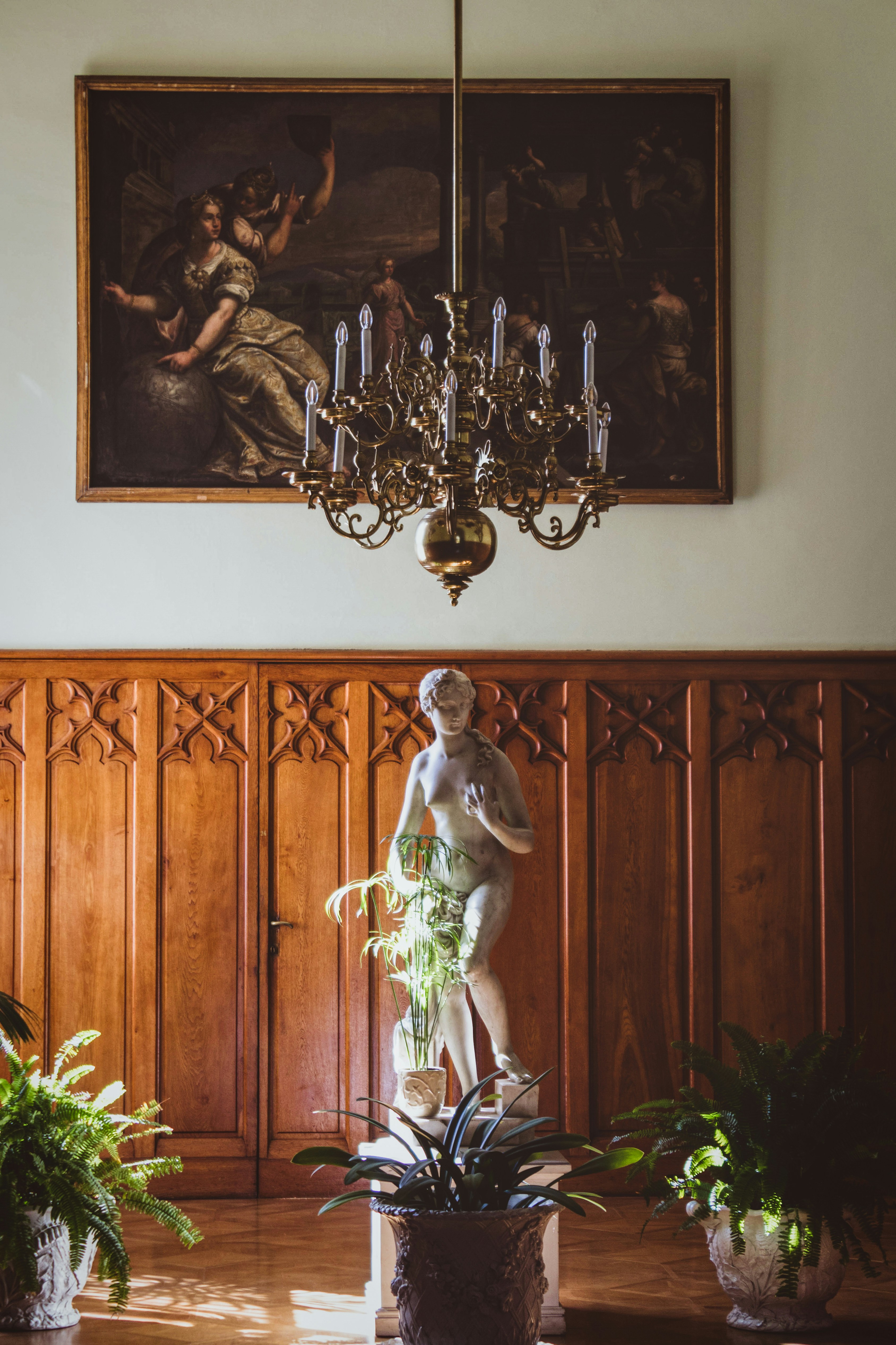 Marble Muse in a Wood-Walled Salon Beneath an Ornate Chandelier