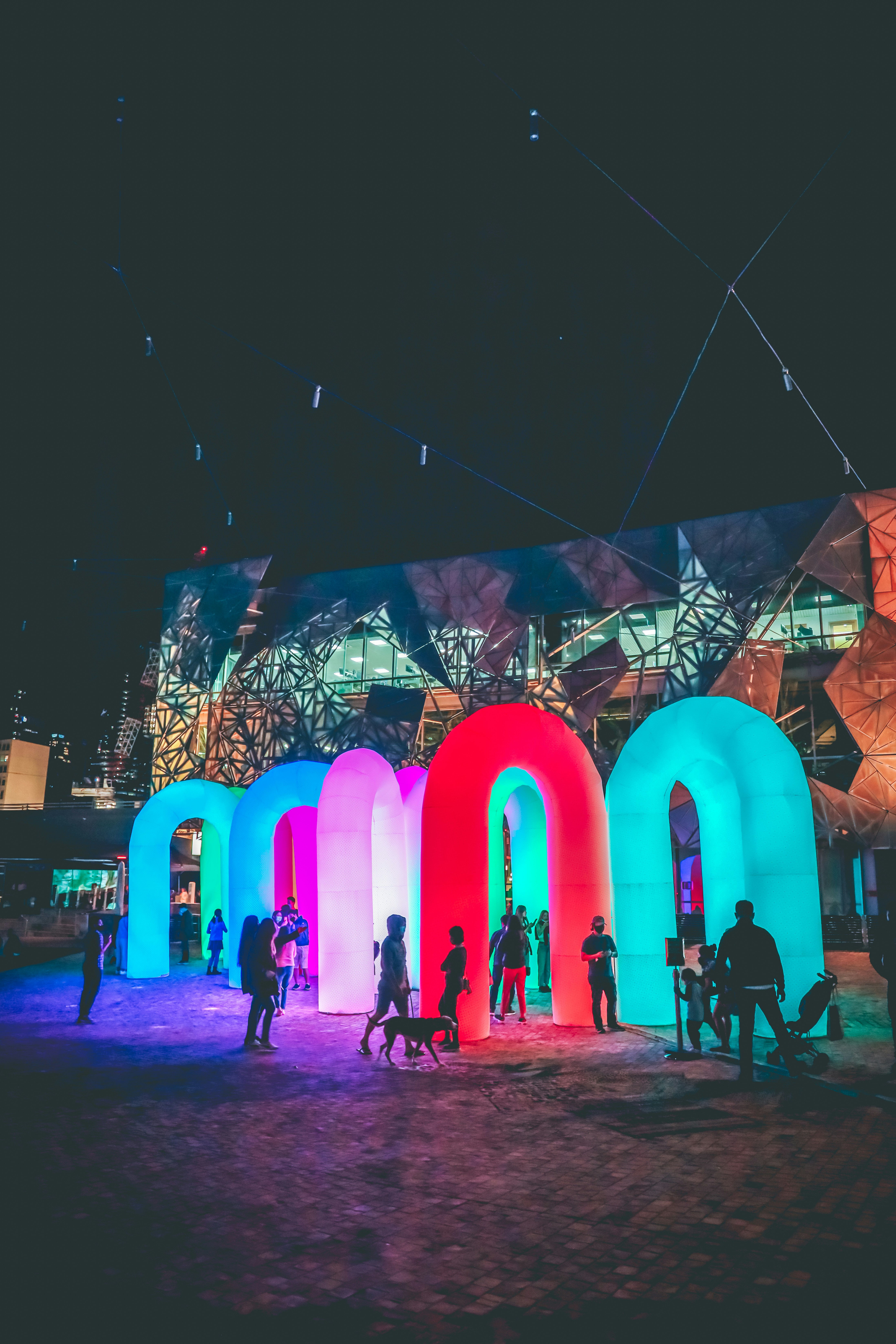 people walking near pink and green building during nighttime