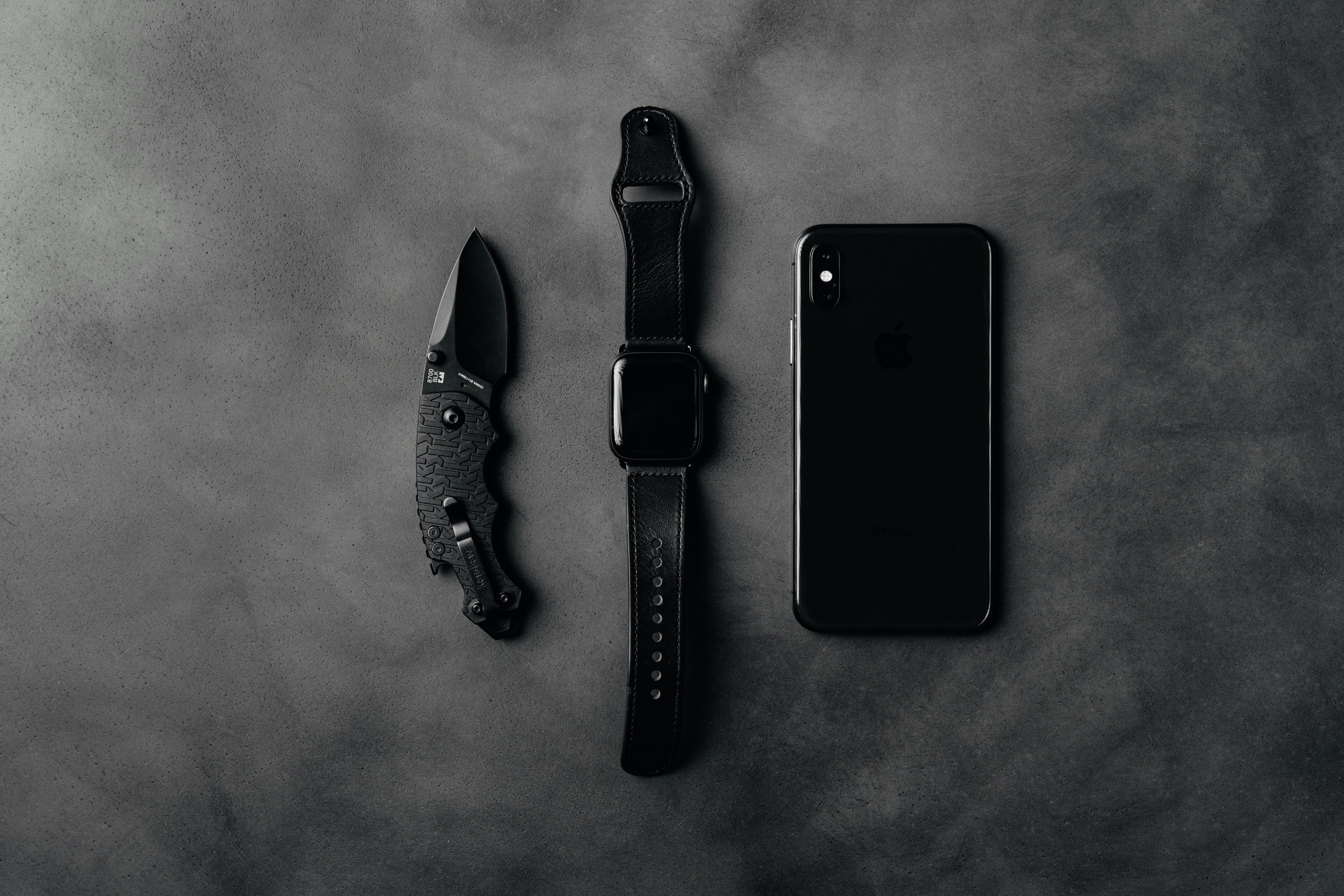 Monochrome Triad: Knife, Watch, and Phone on a Slate Surface