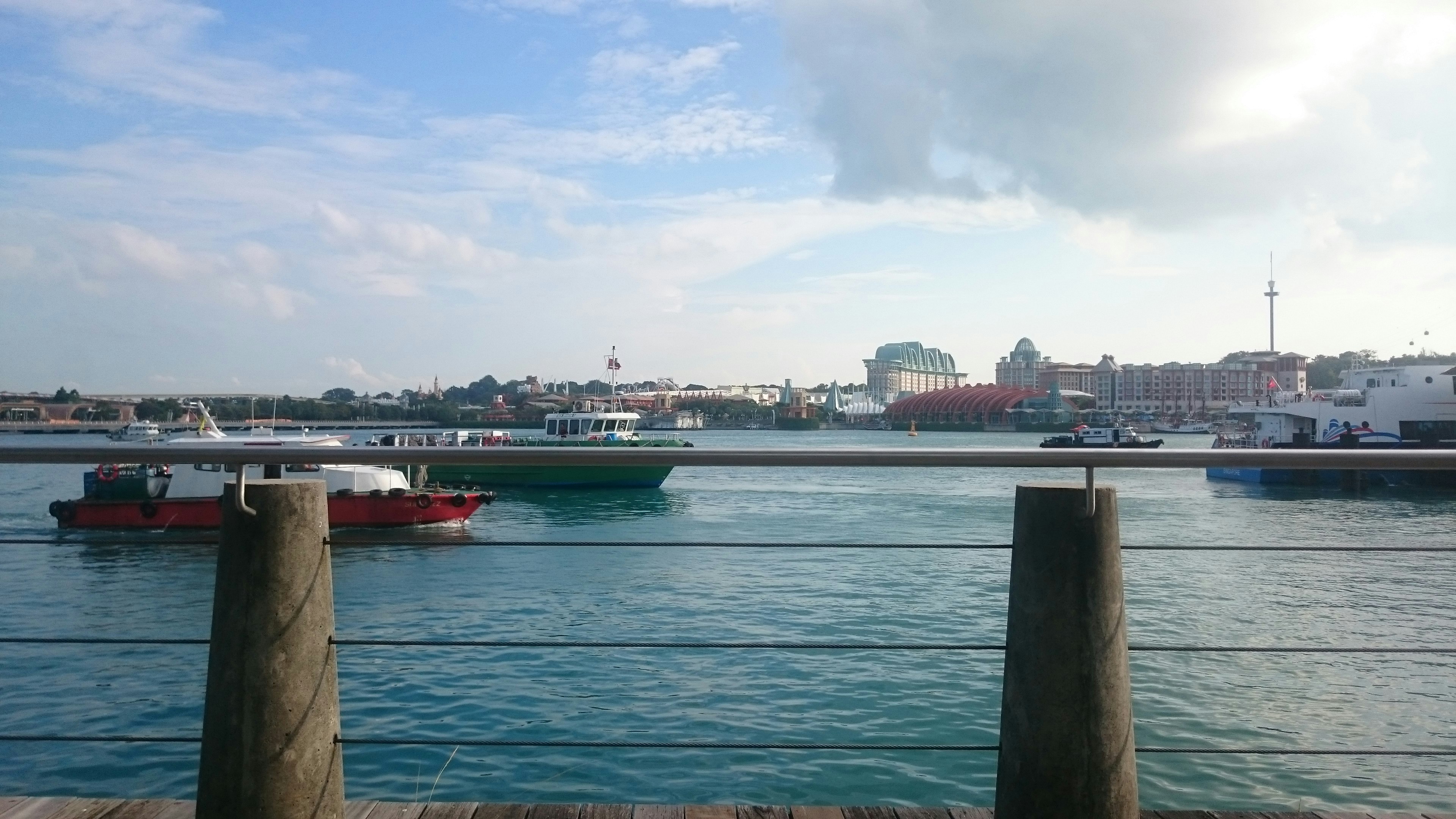 Vessels navigate a tranquil harbor against a backdrop of cityscape and blue skies. The scene captures the essence of daily maritime activities.