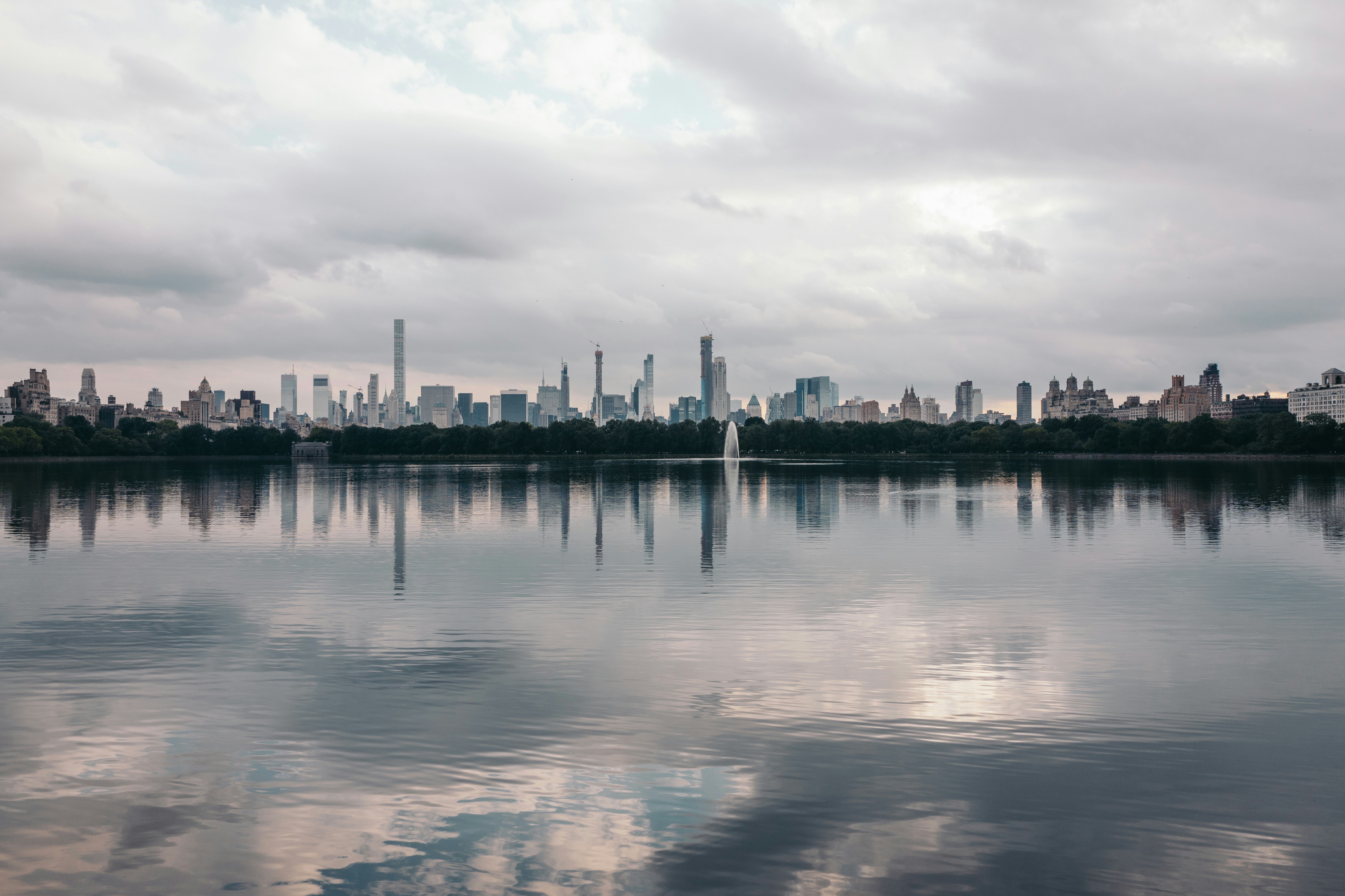 Mirror City Across a Glassy River Under a Cloud-Washed Sky