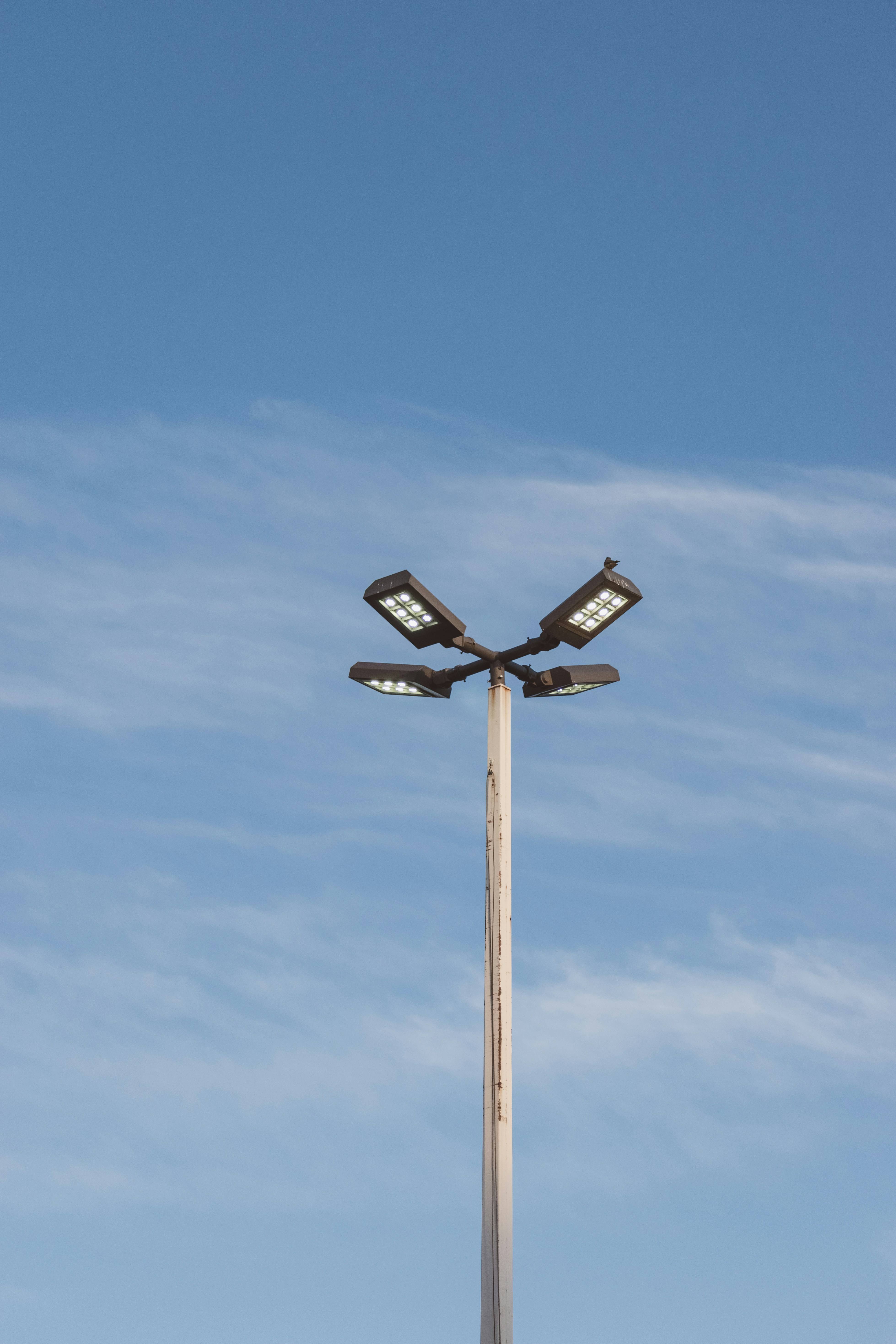 Streetlight with four LED fixtures against a clear blue sky, showcasing contemporary urban infrastructure.