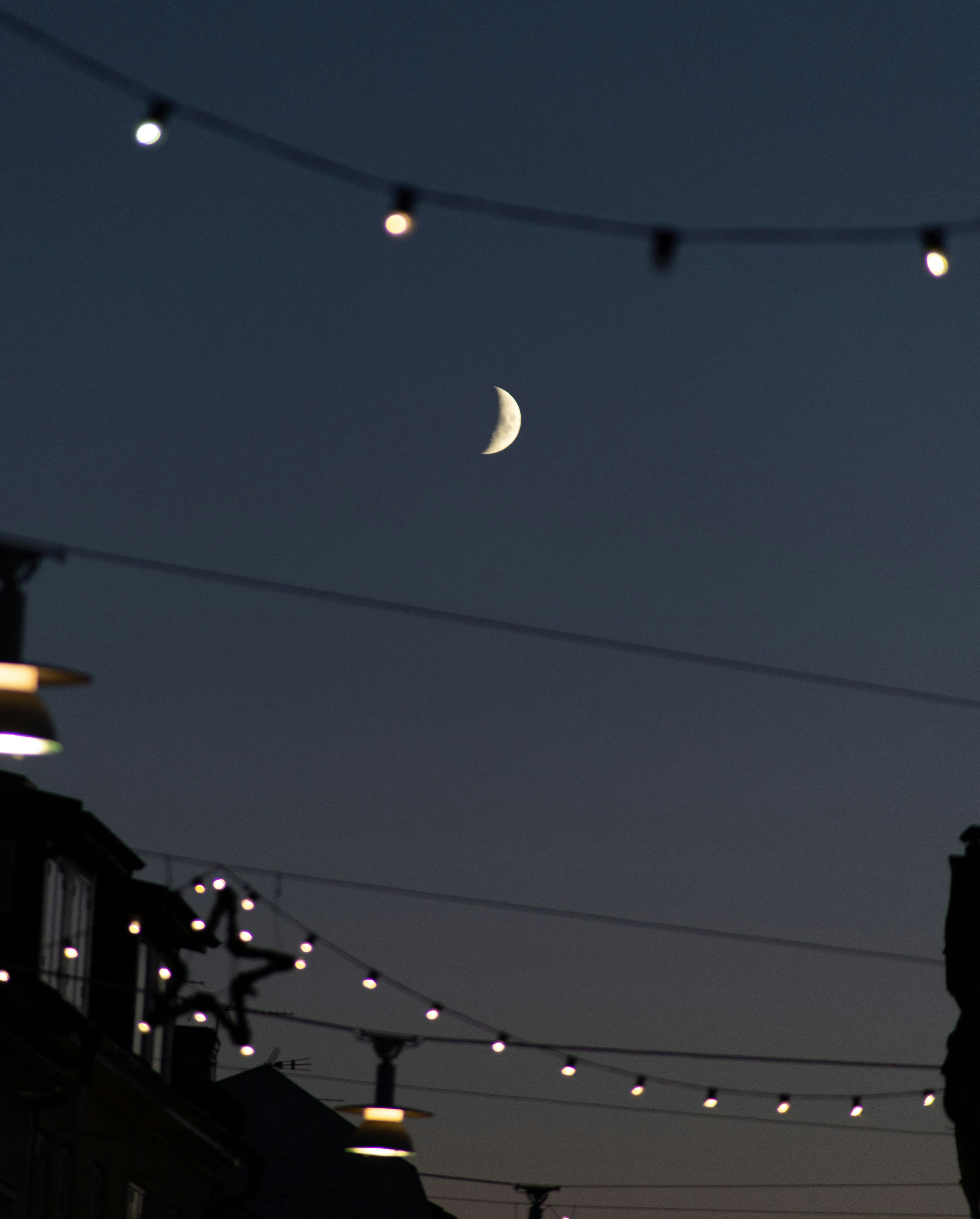 Crescent Moon Above a Velvet Night Strung with Warm Lights