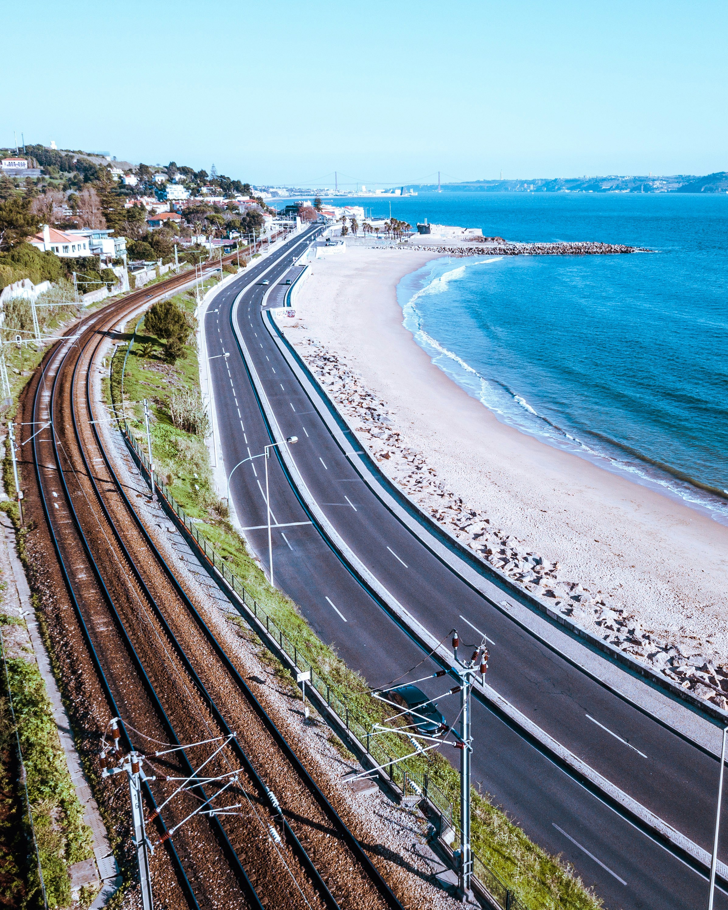 Coastal Ribbon: An Aerial Study of a Curving Highway Beside Train Tracks and Sea