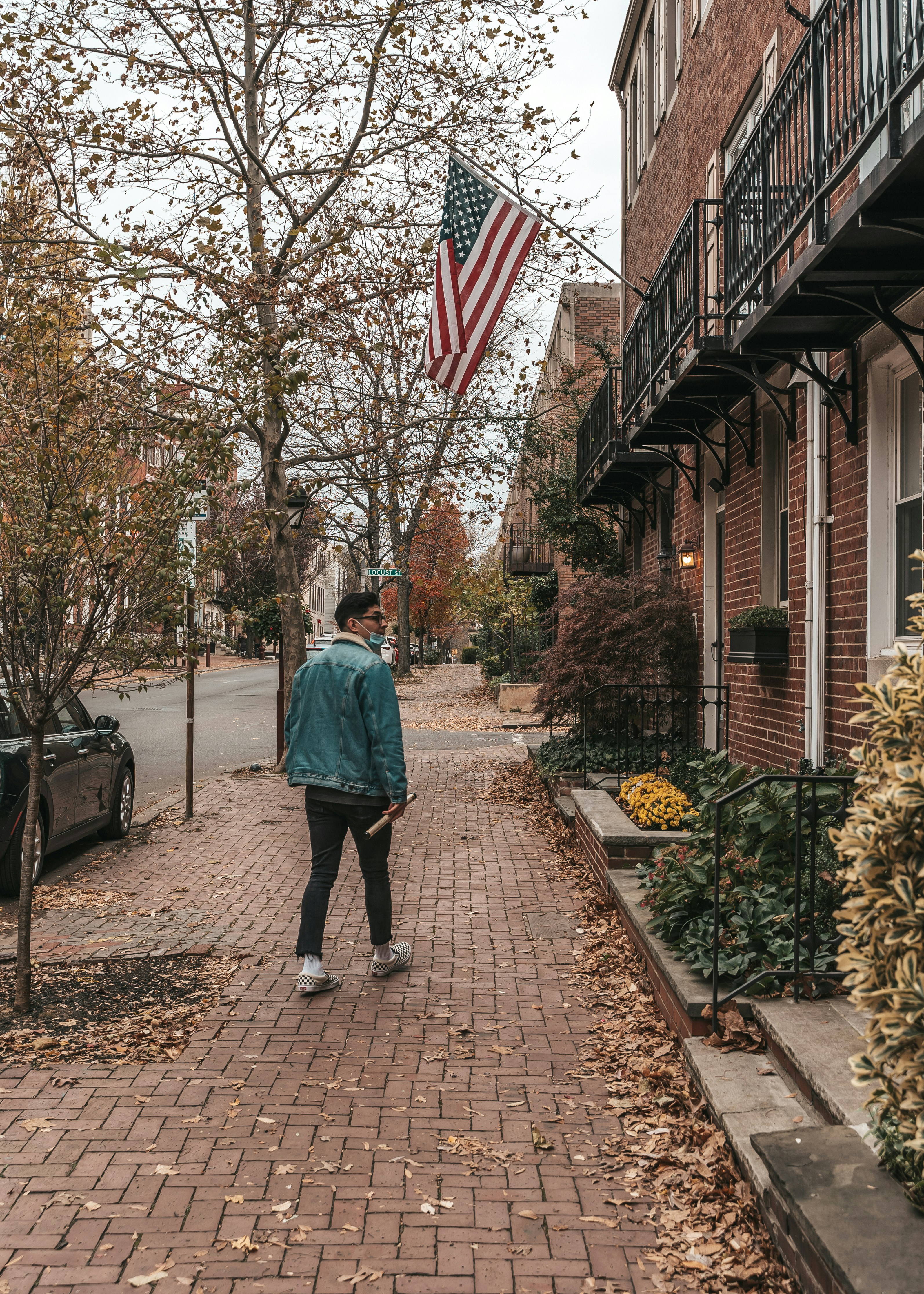 Flag Over a Quiet Brick Street: A Lone Walker in Autumn