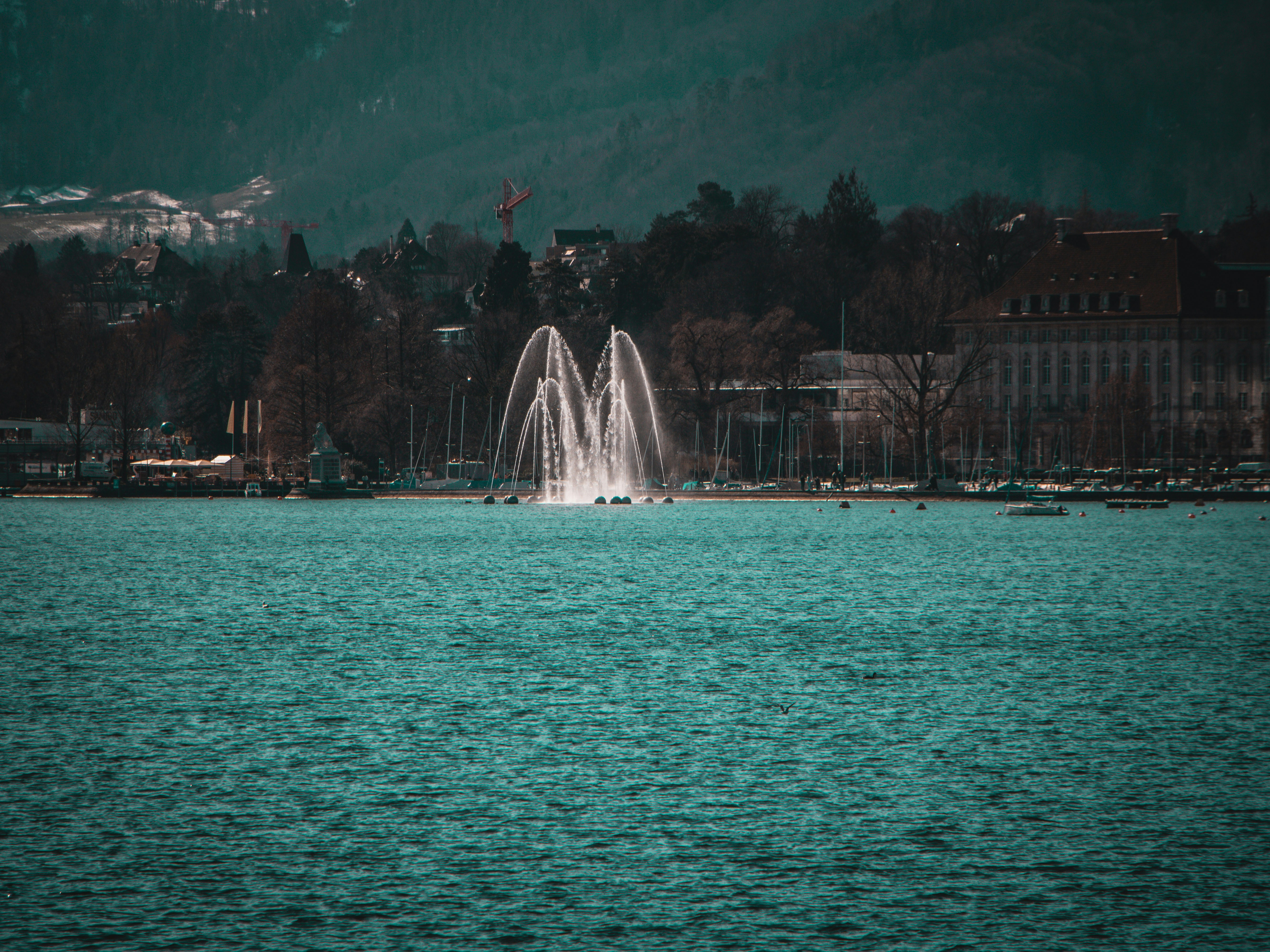 Teal-Lake Fountains: Quiet Symmetry Against Alpine Silhouette