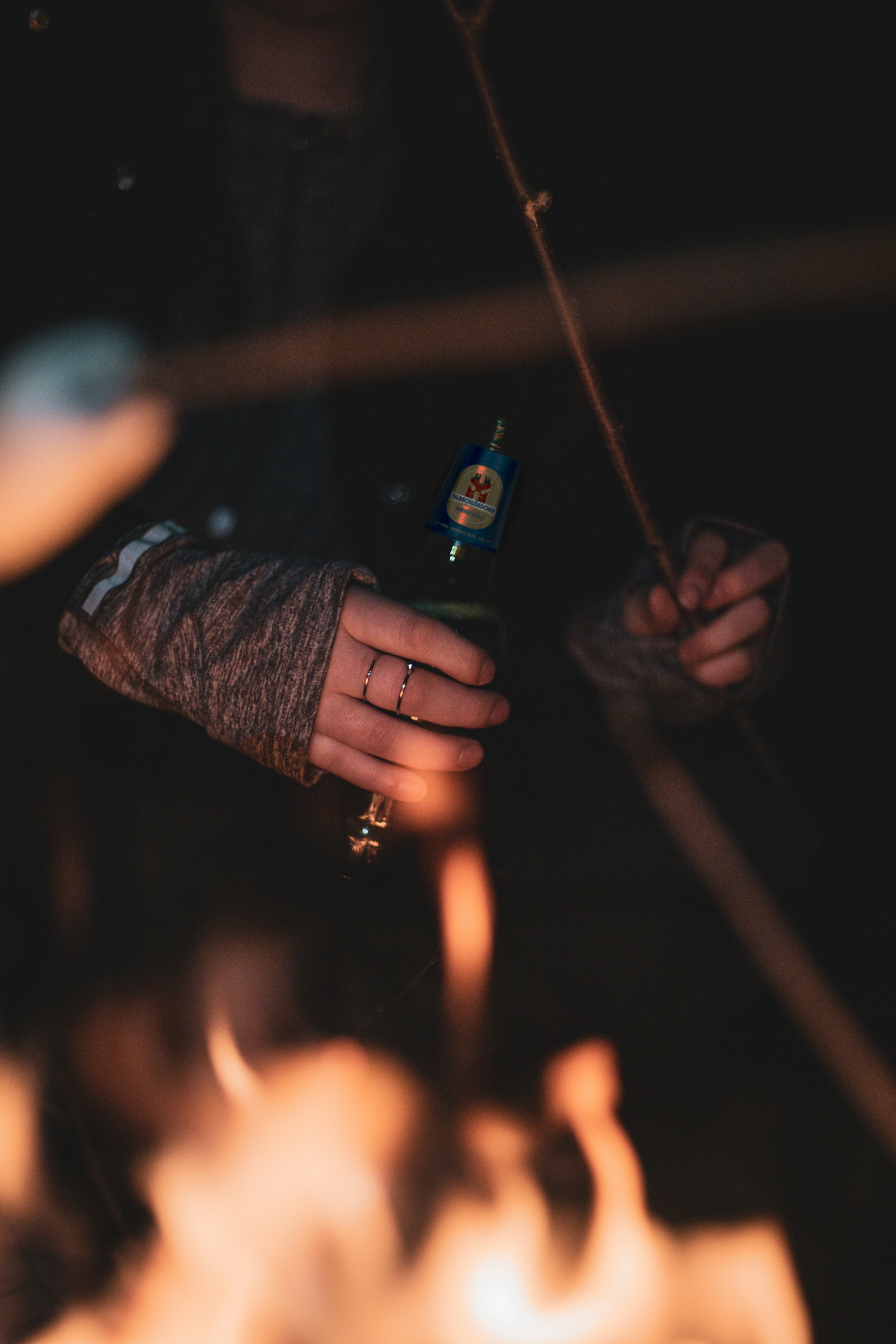 Friends sitting together with marshmallows and beer at a campfire