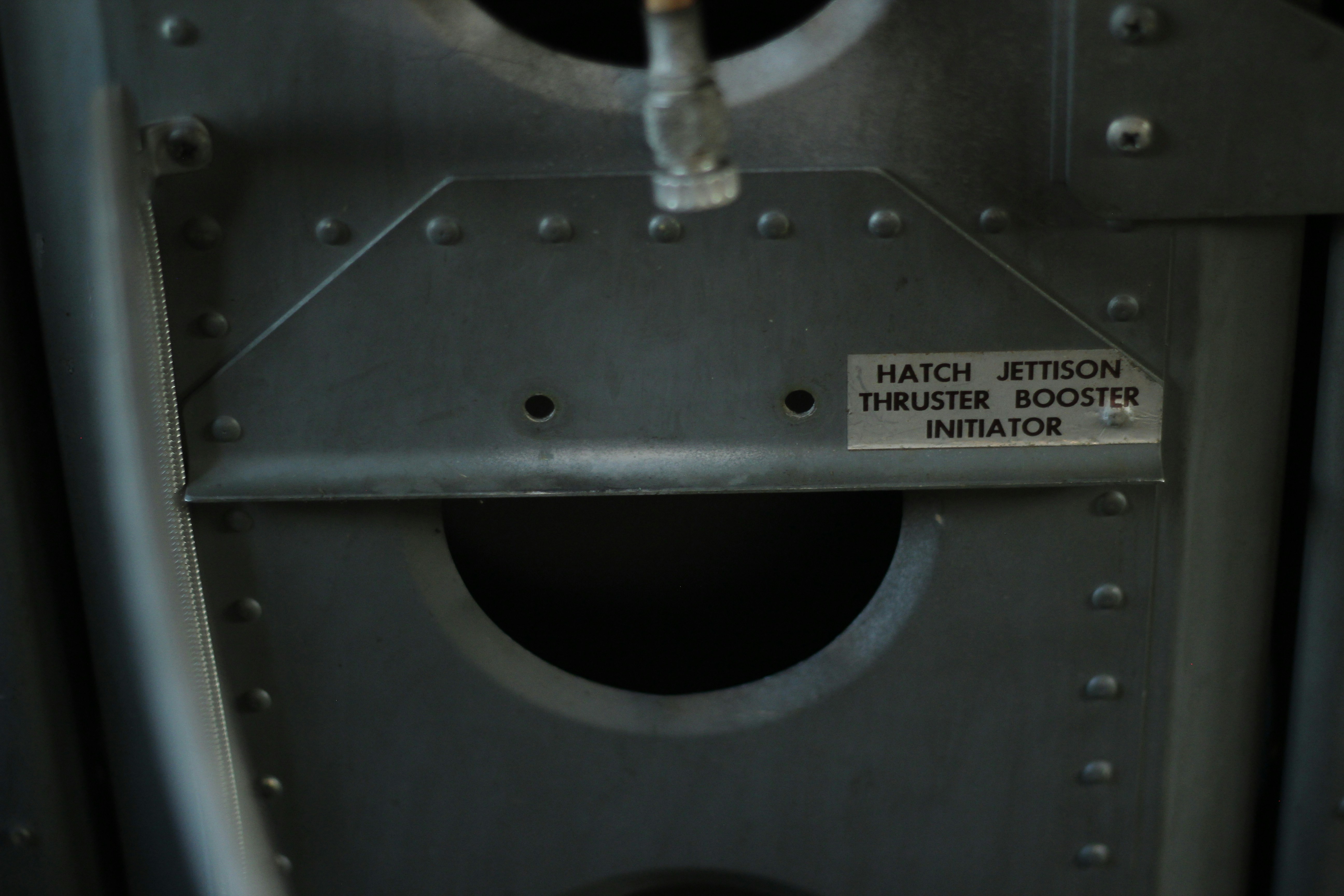 Detailed view of a metal panel featuring a label for a thruster booster initiator, showcasing the intricate components of aerospace machinery.