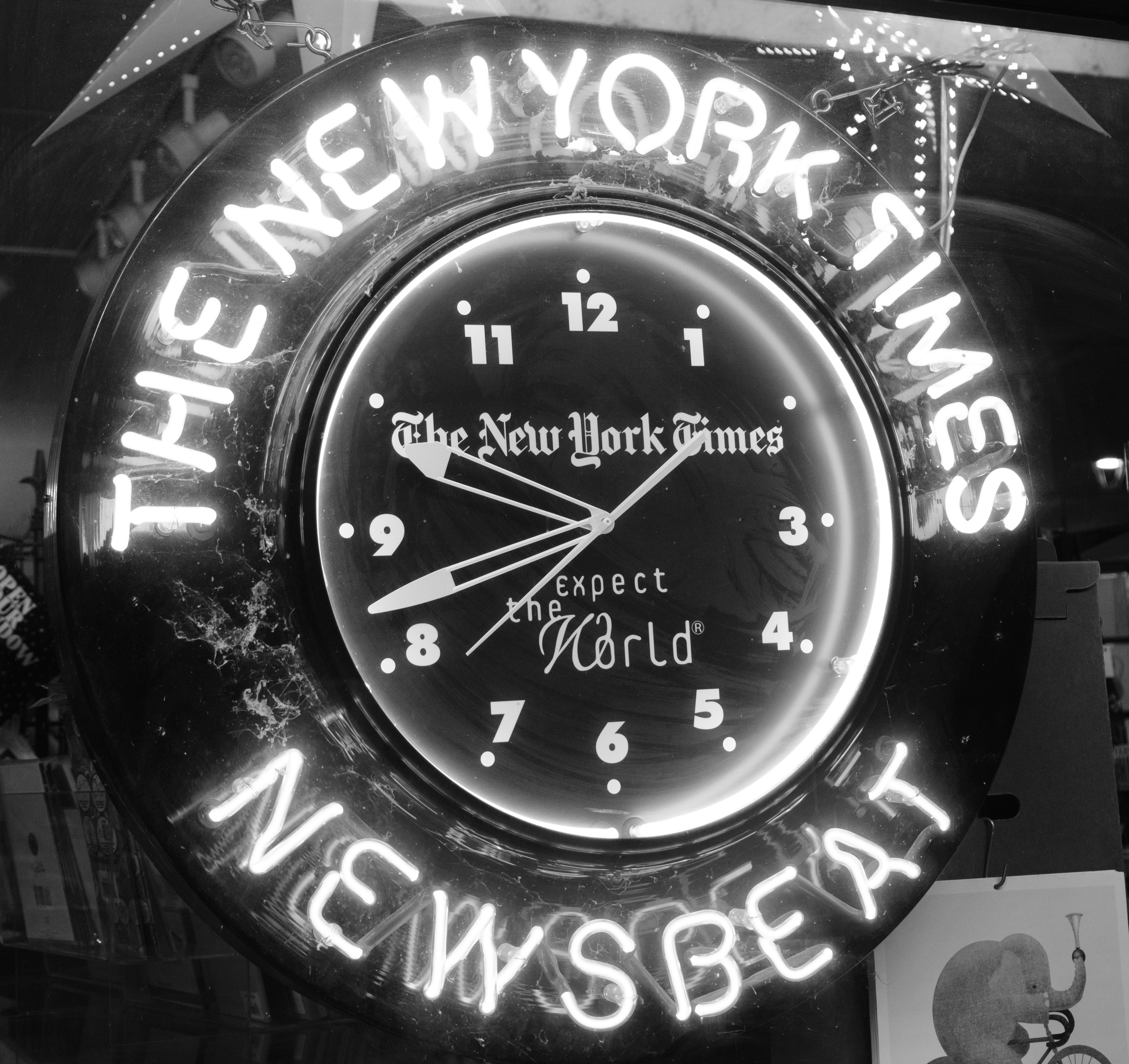 Neon clock featuring 'THE NEW YORK TIMES' and 'NEWSBEAT' in a vintage design, showcasing the passage of time against a backdrop of light.