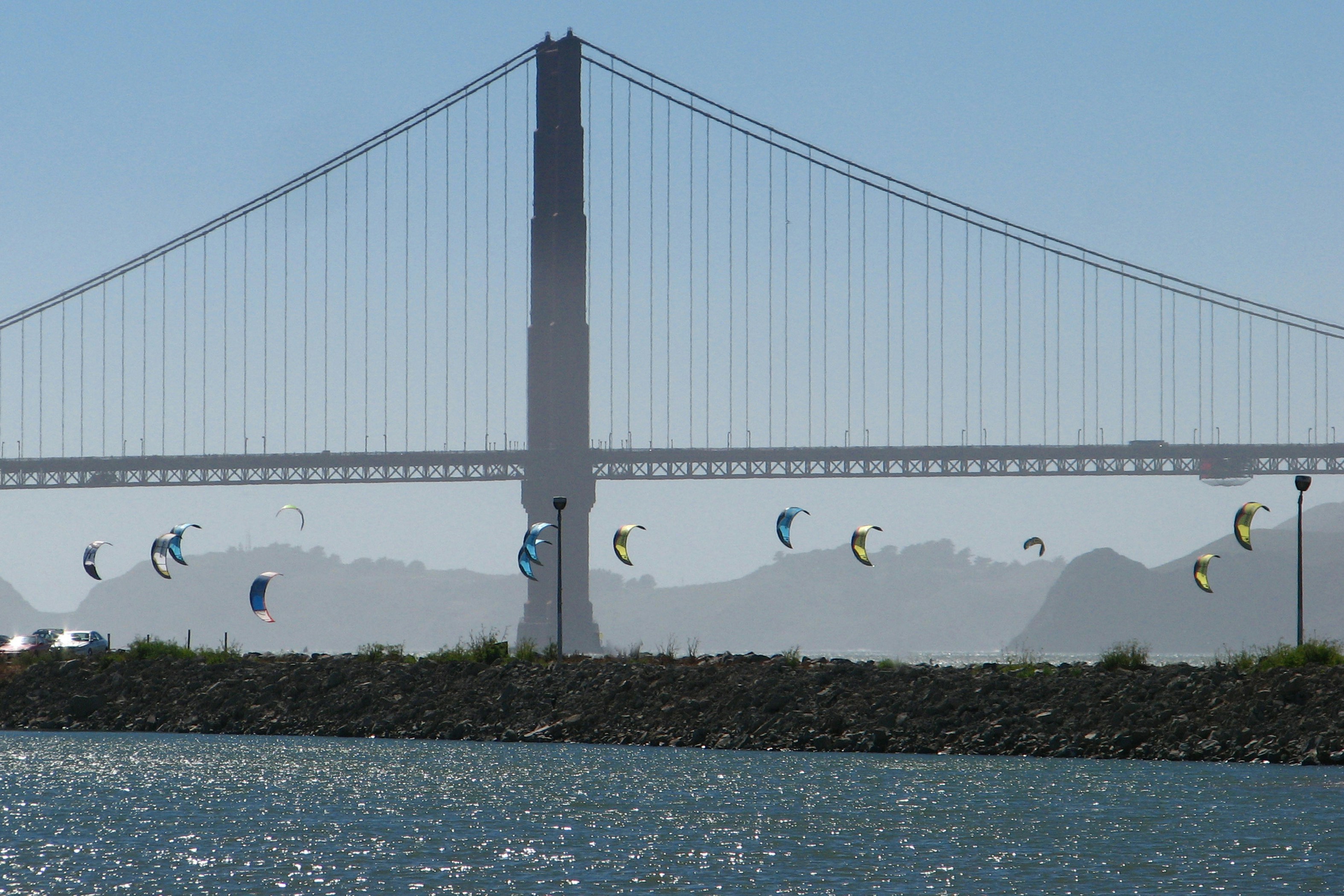Colorful kites fluttering in the breeze against the backdrop of the Golden Gate Bridge, showcasing a vibrant day by the water.