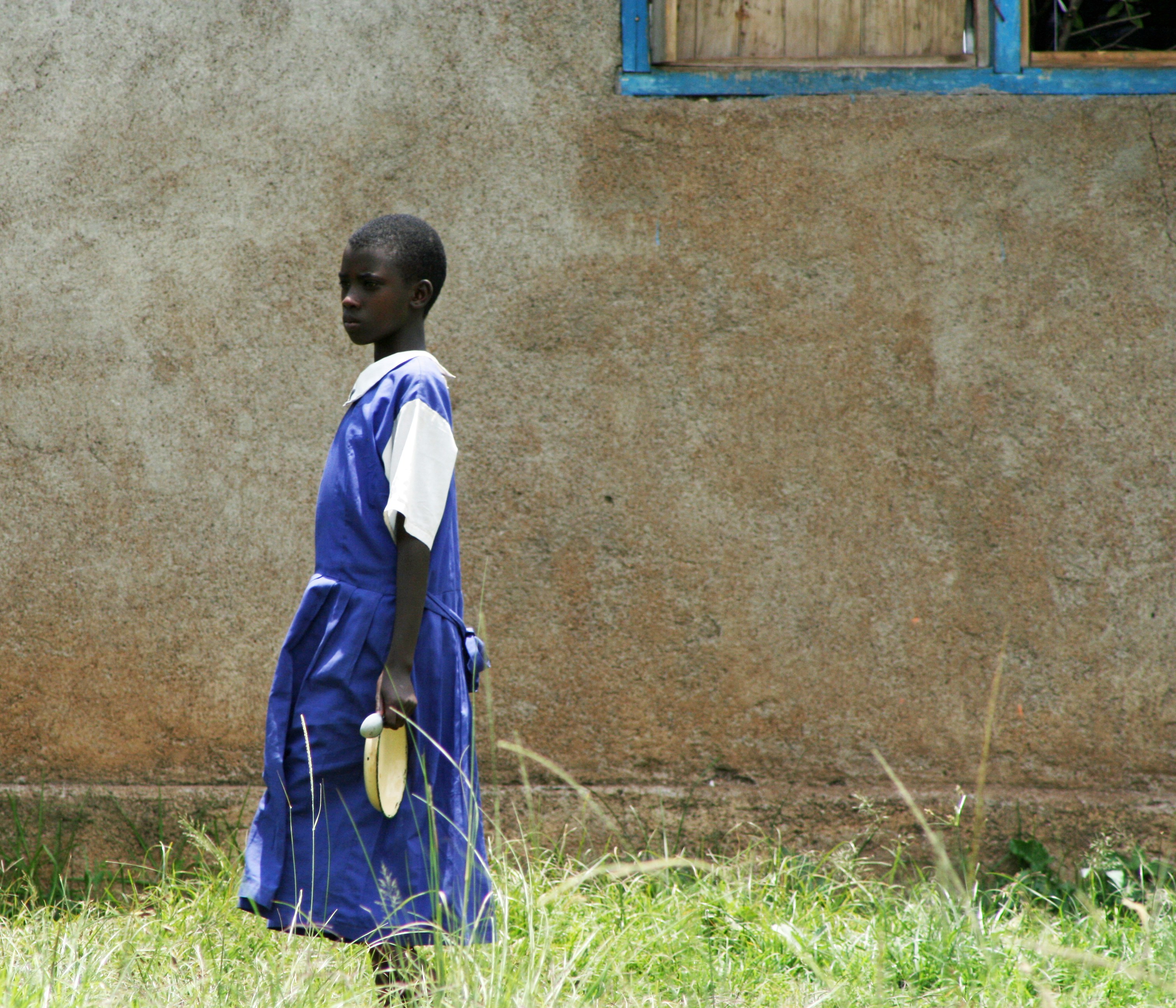 Profile in Cobalt: a lone student against a sunlit, weathered wall