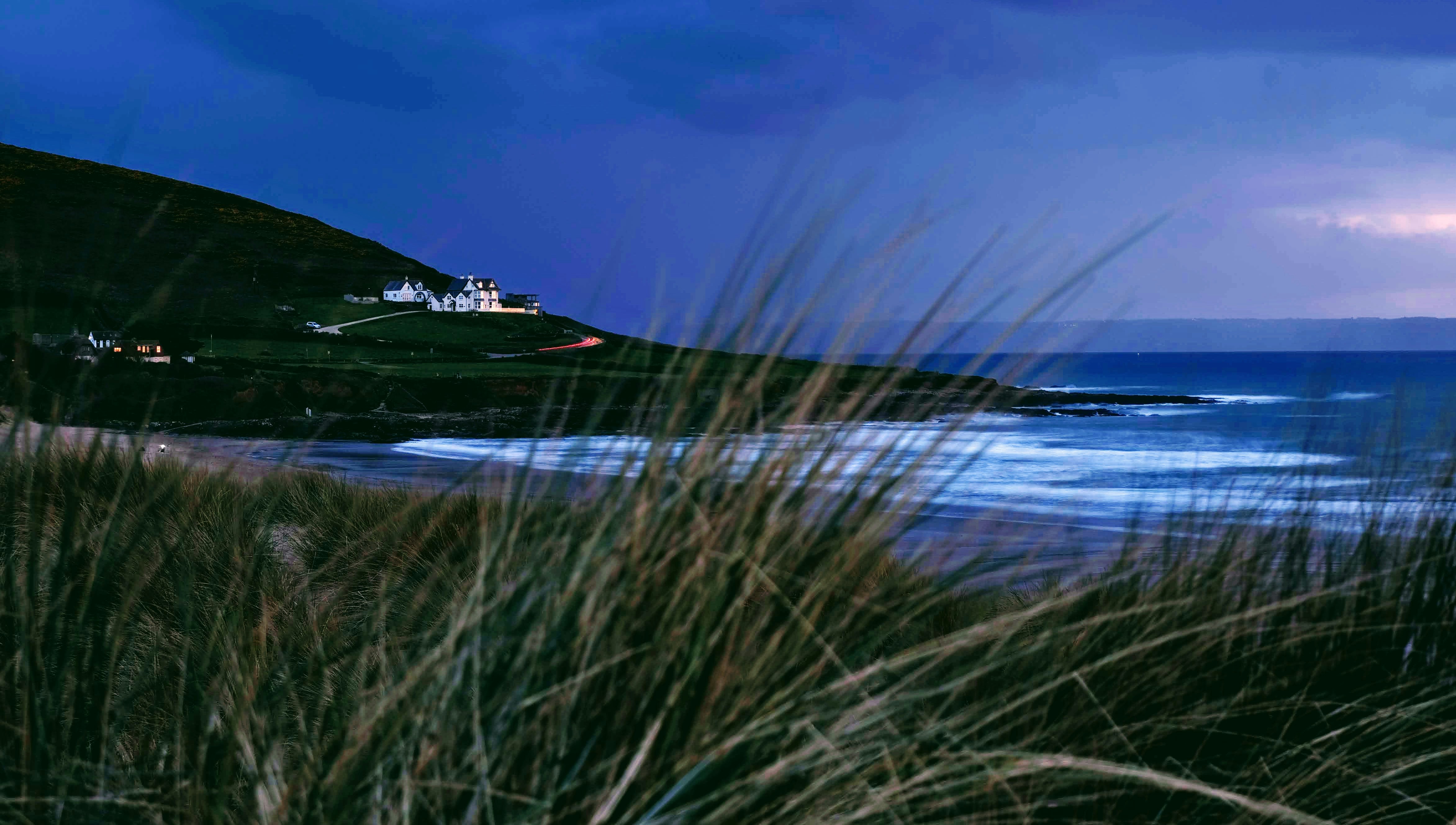 Croyde Bay at night with gentle waves meeting the shore under a moody sky.