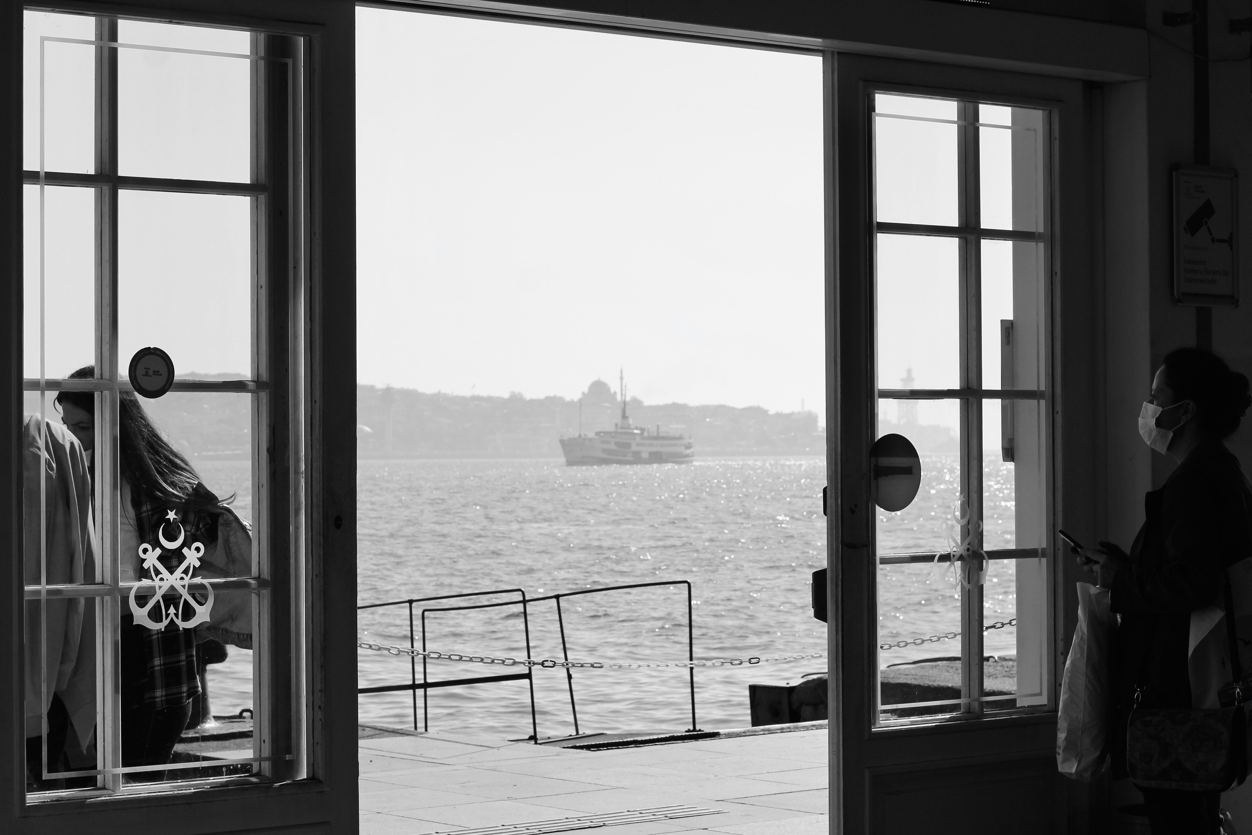 Threshold to the Harbor: A Distant Vessel Framed by Open Doors