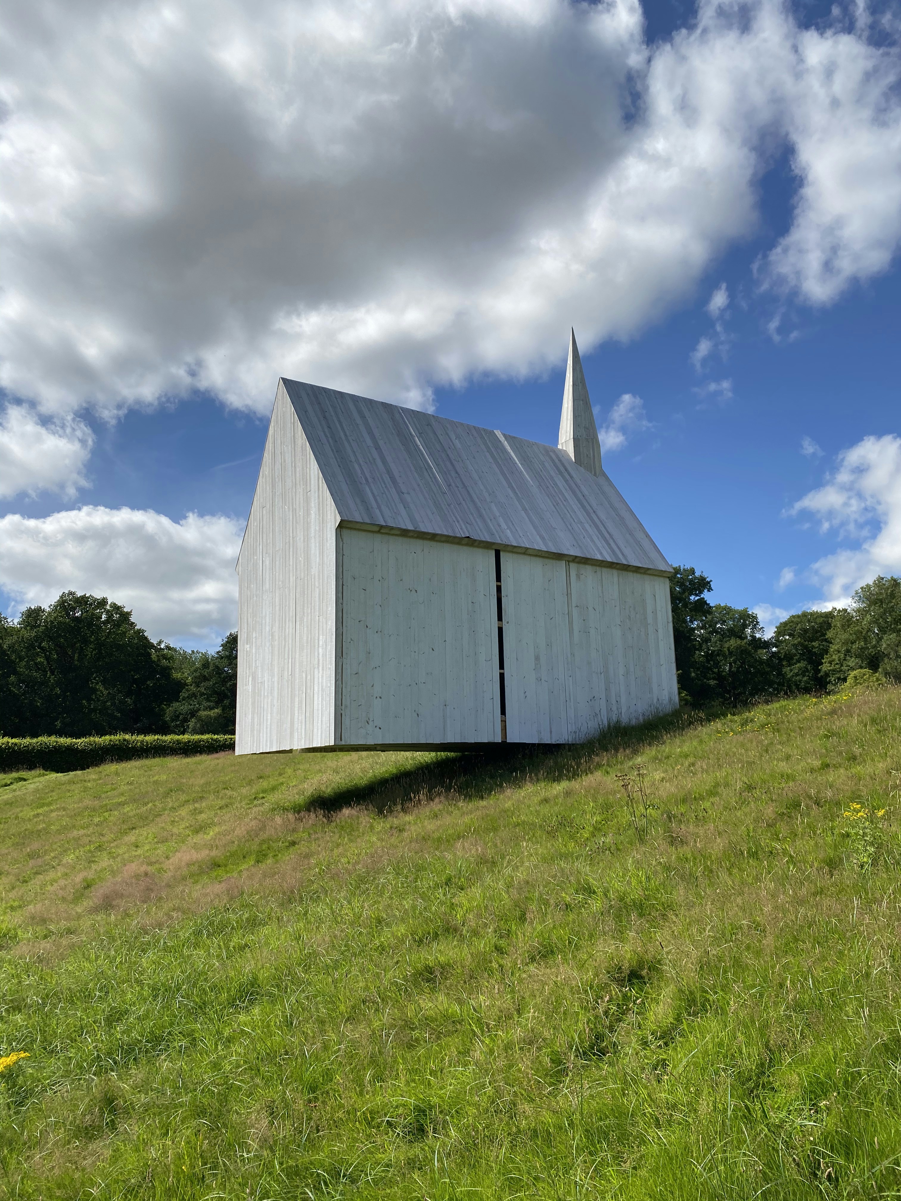 White wooden barn on green grass field under blue sky and white clouds ...