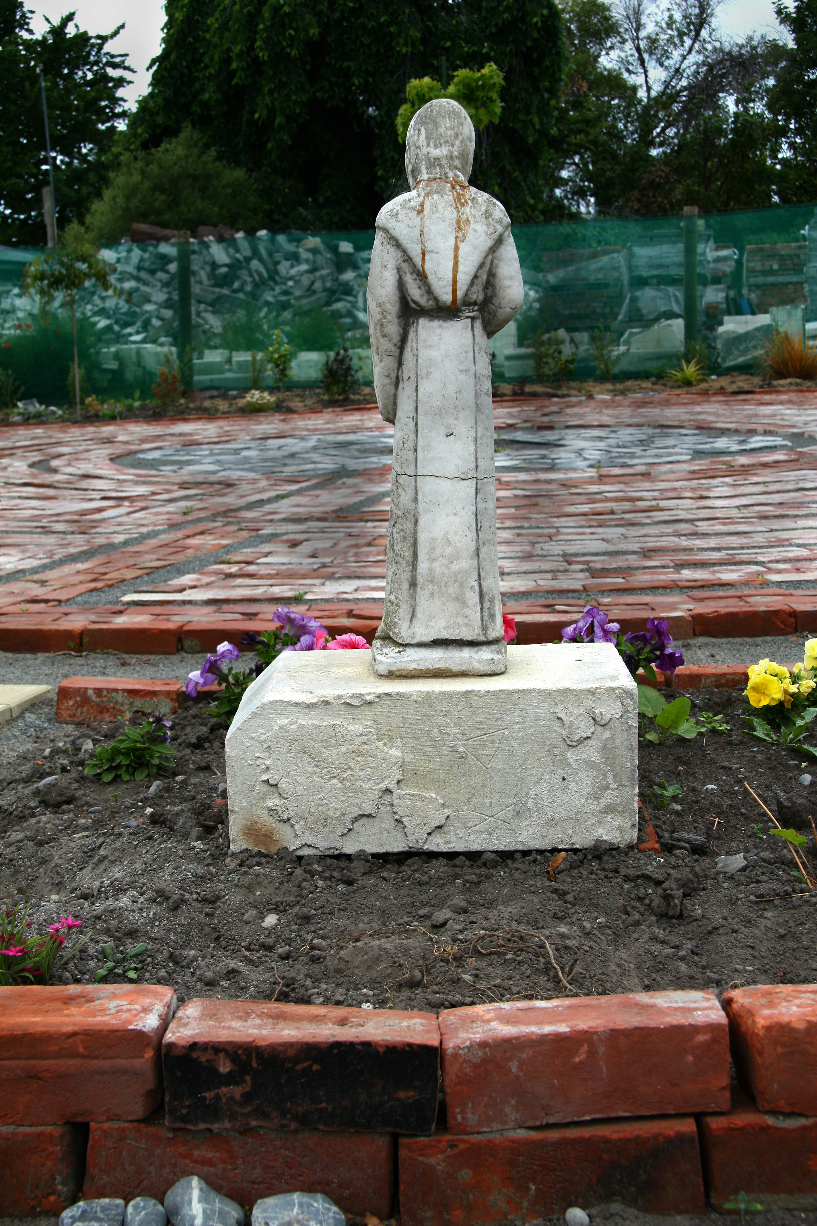 Weathered statue in a circular brick garden embankment