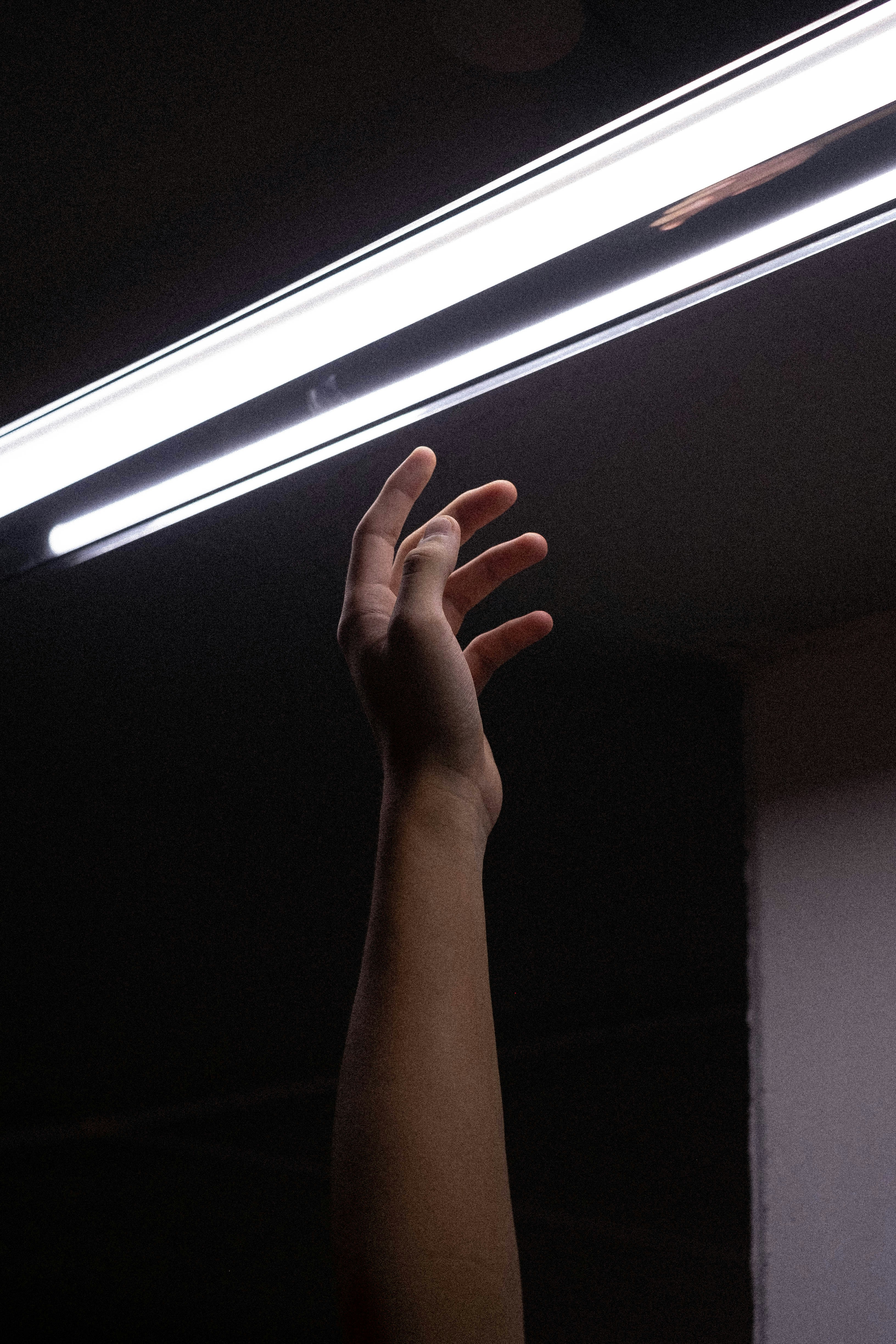 Reach for the Neon Beam: A solitary hand under a fluorescent rush