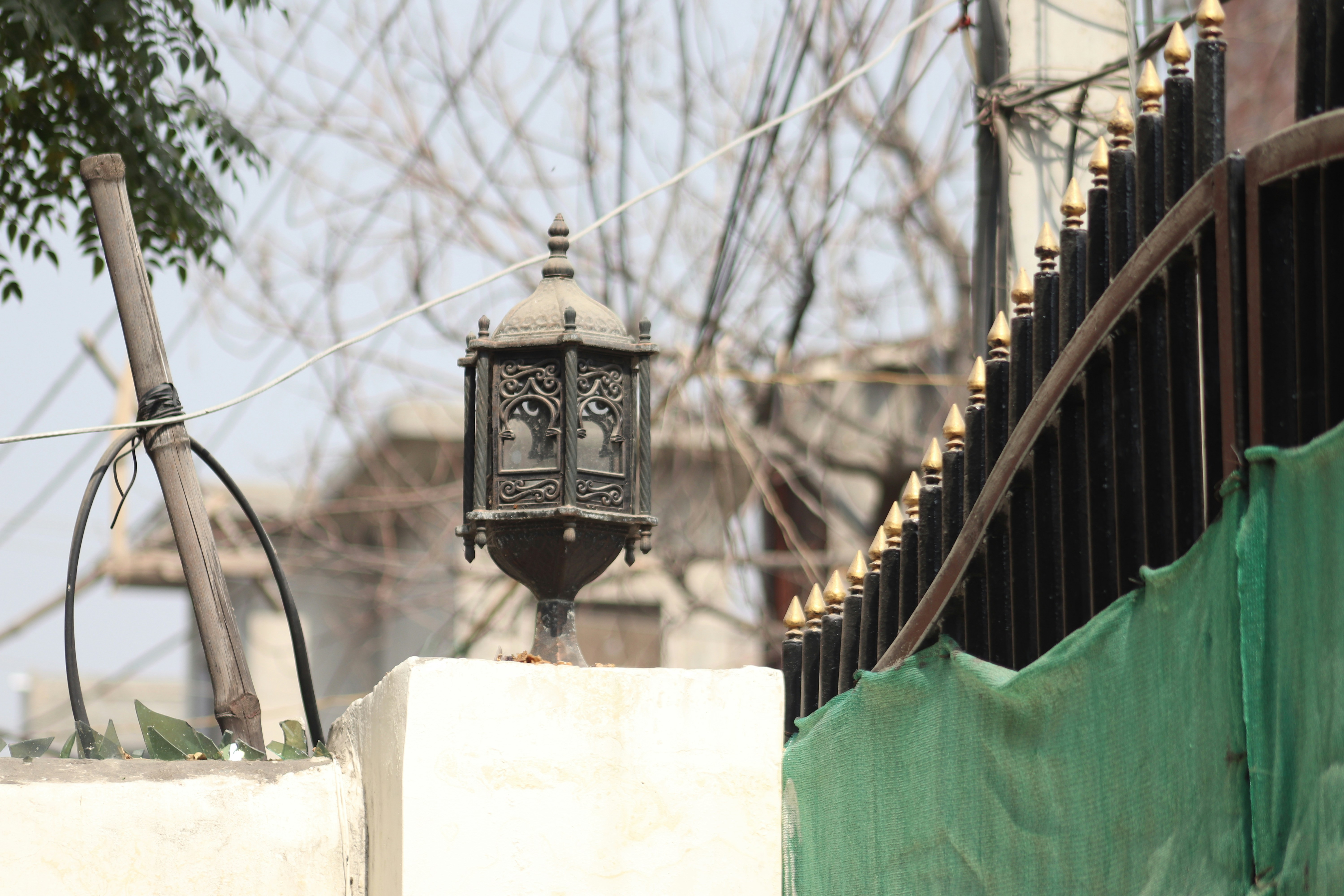 Ornate lantern perched above a sunlit wall