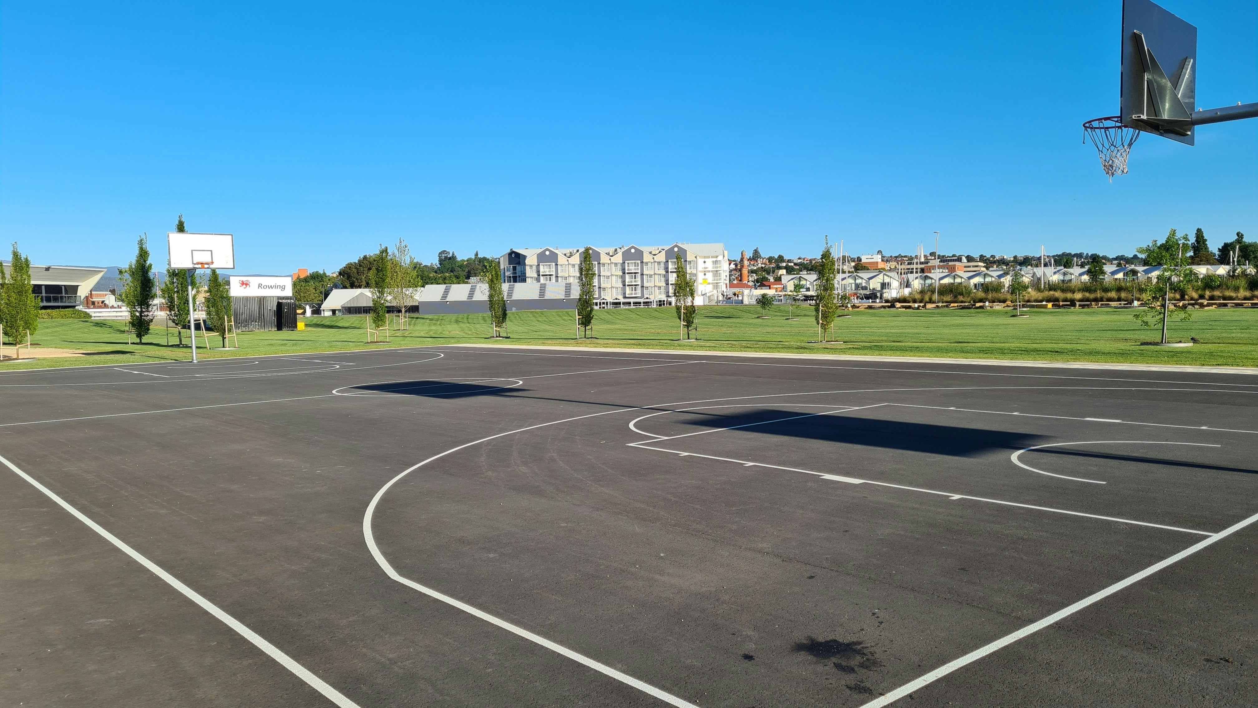 Open-Air Geometry: An Empty Basketball Court Beneath a Bright Blue Sky