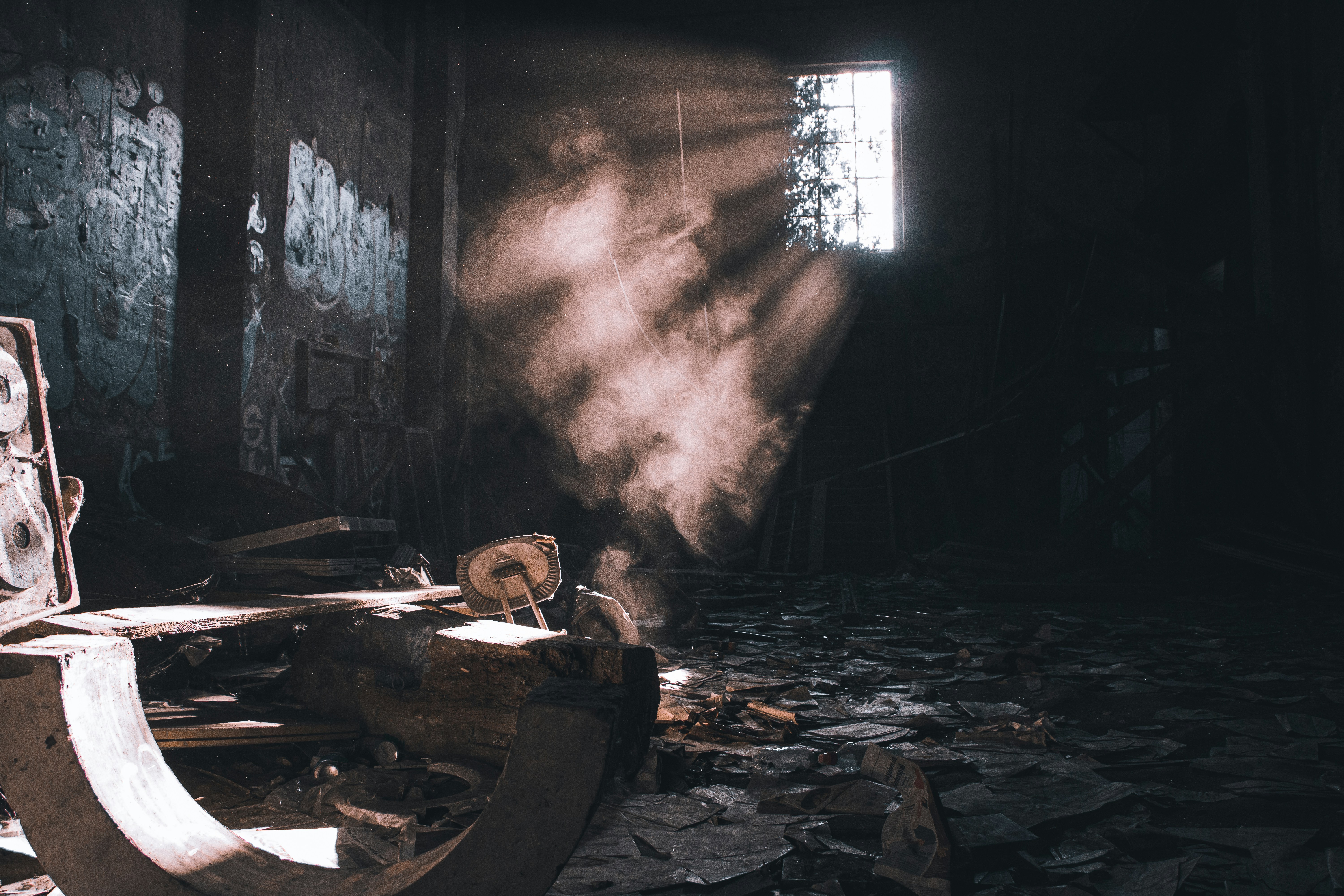 Sunlight filters through a window, illuminating dust in an abandoned, debris-strewn room.