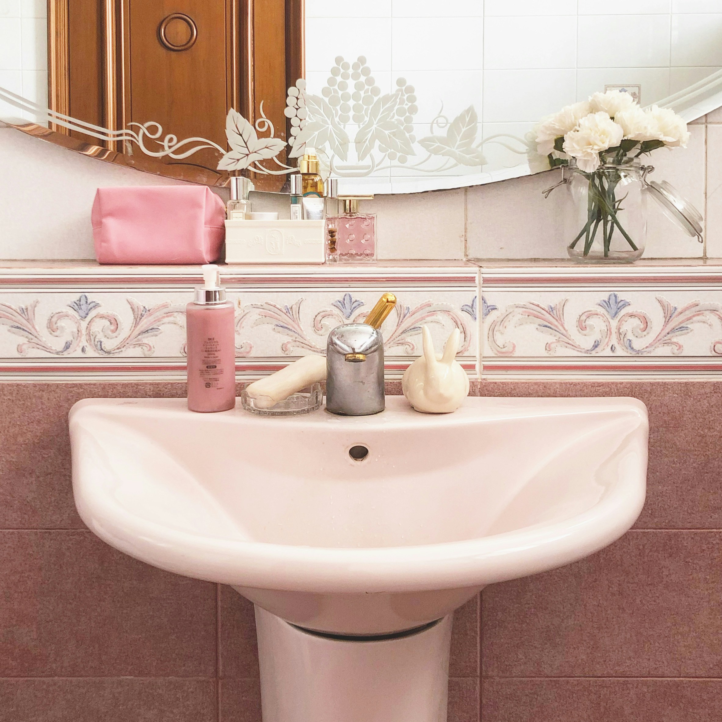 Elegant bathroom sink adorned with beauty products and fresh flowers, reflecting a sense of calm and personal care.