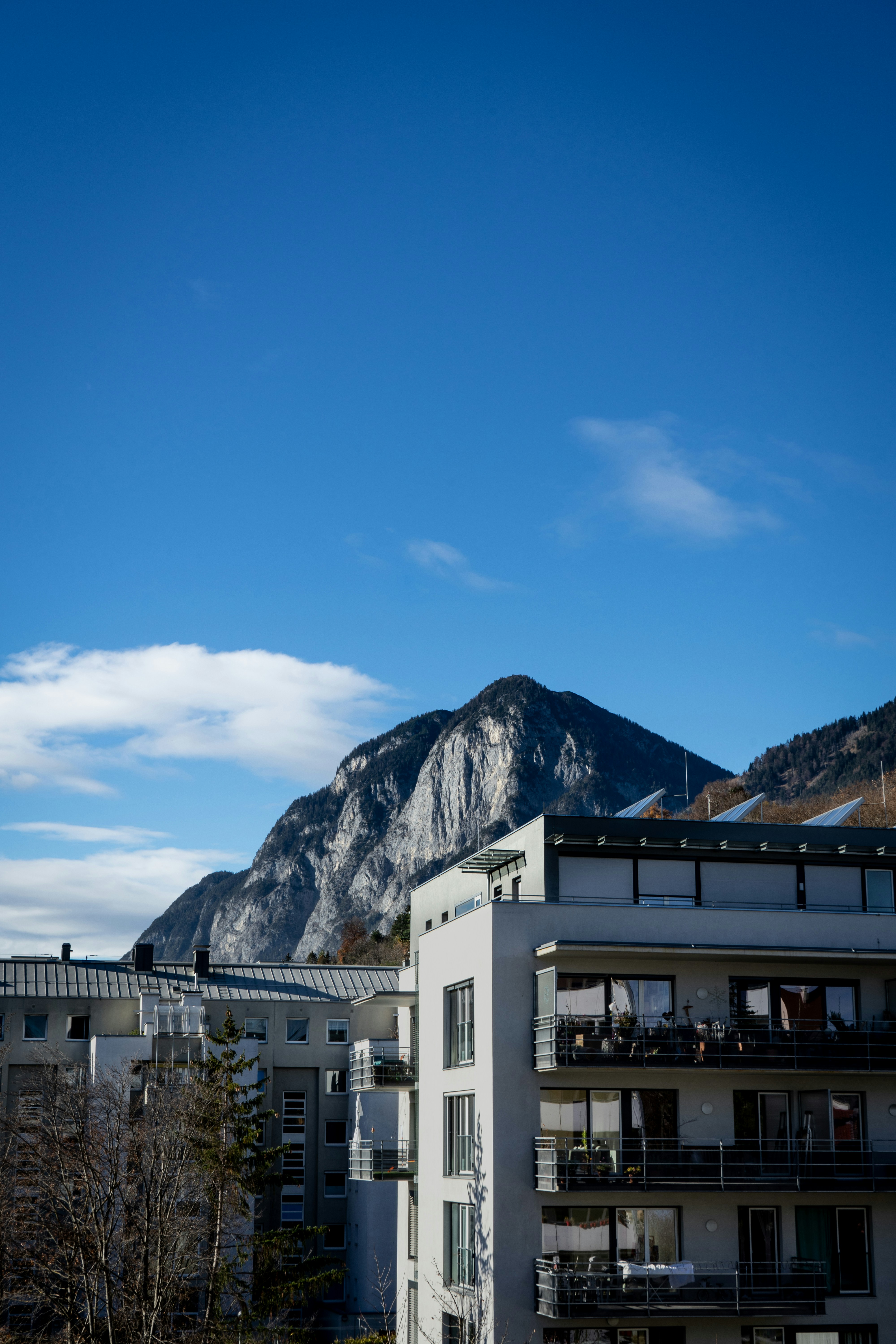 White and brown concrete building near mountain under blue sky during ...
