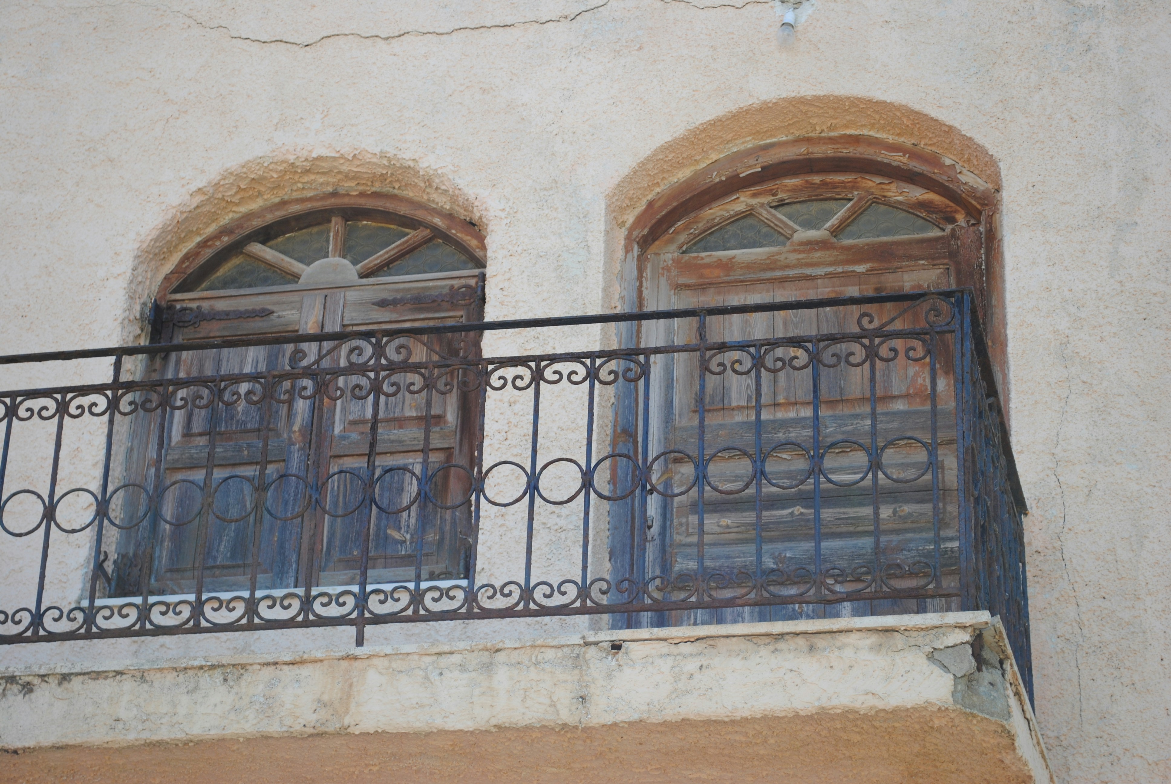 Balcony on historic building in Crete | black metal gate on brown concrete building